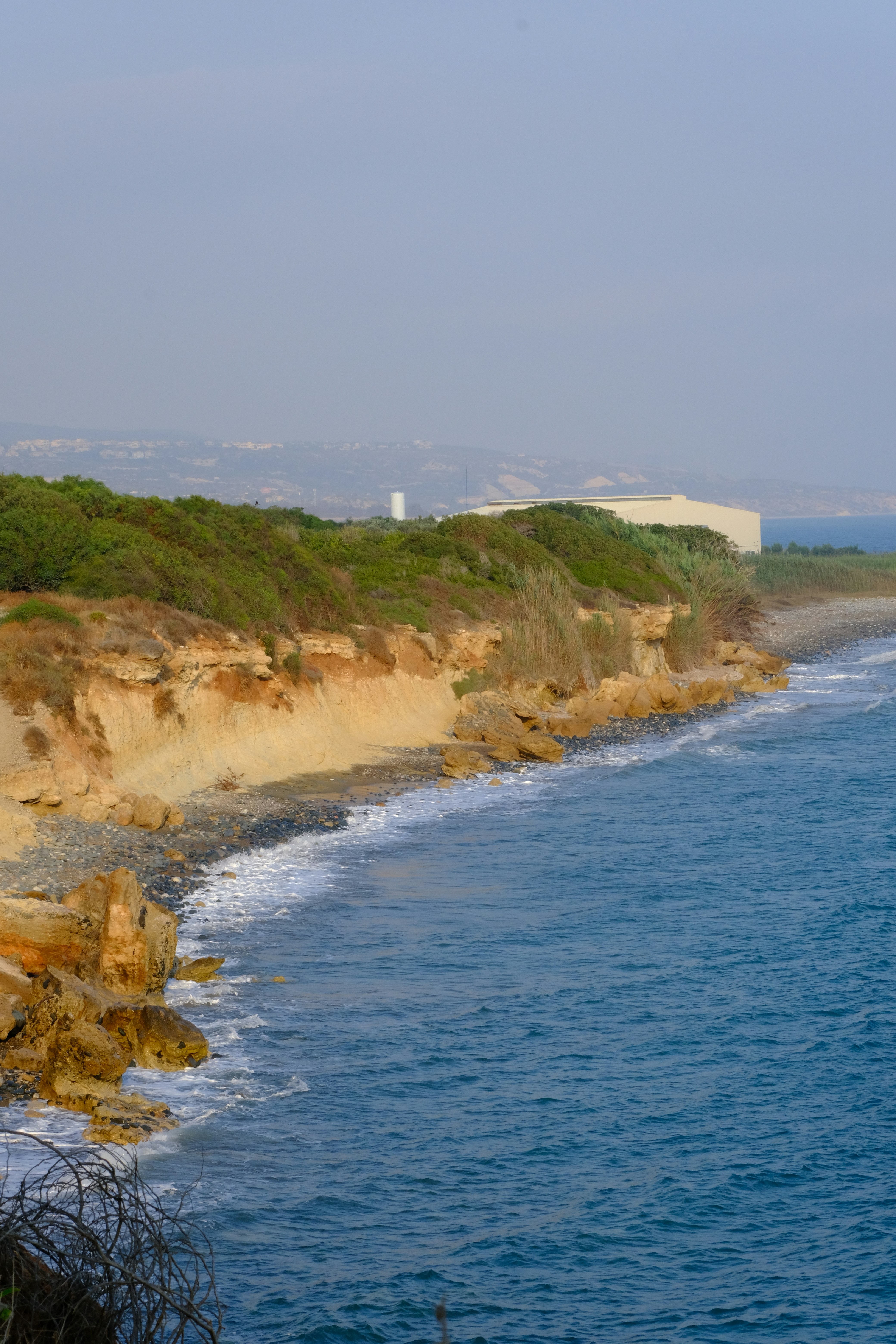 Coastal cliffs with green vegetation and blue ocean waves.