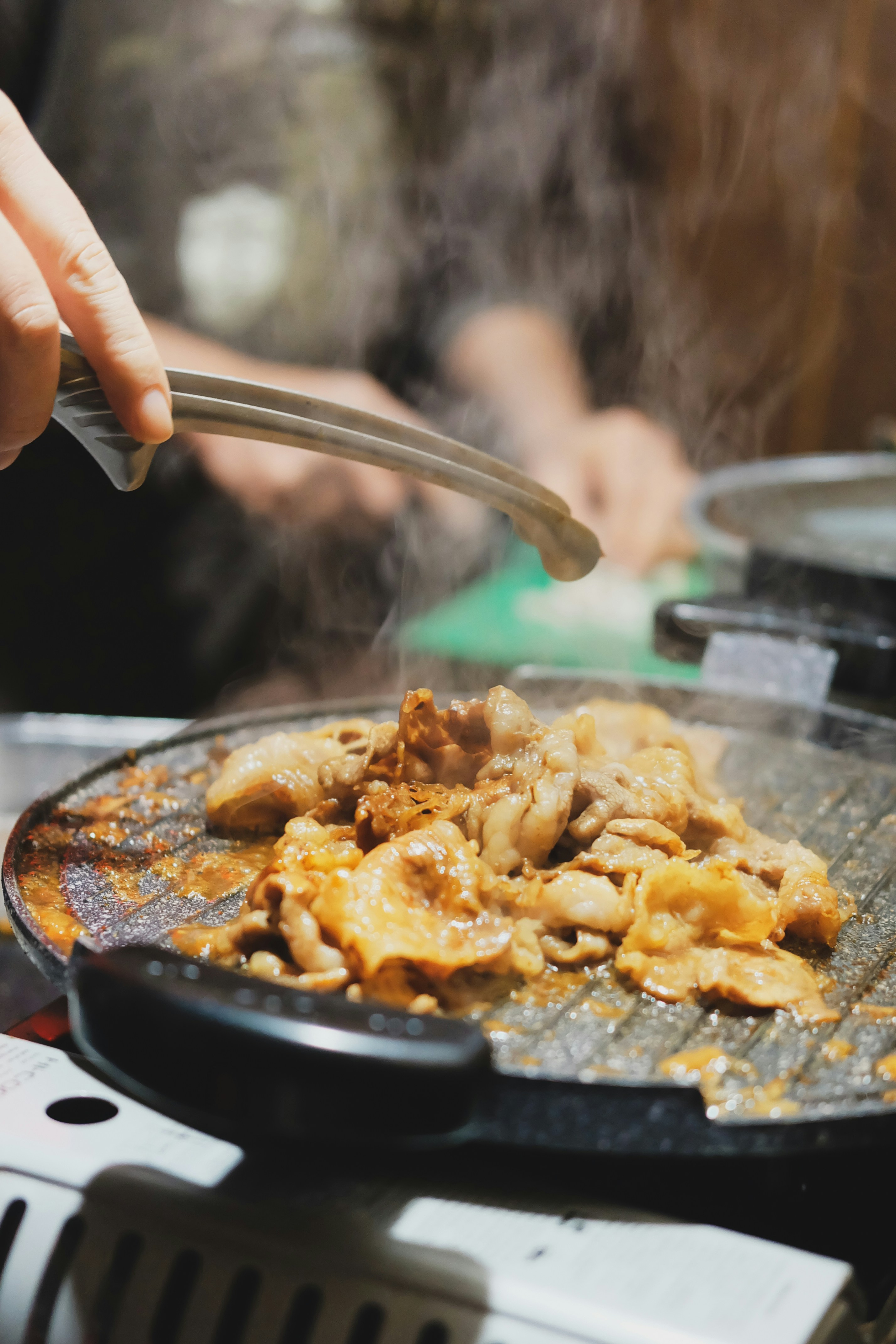 Meat sizzling on a hot grill with steam rising.