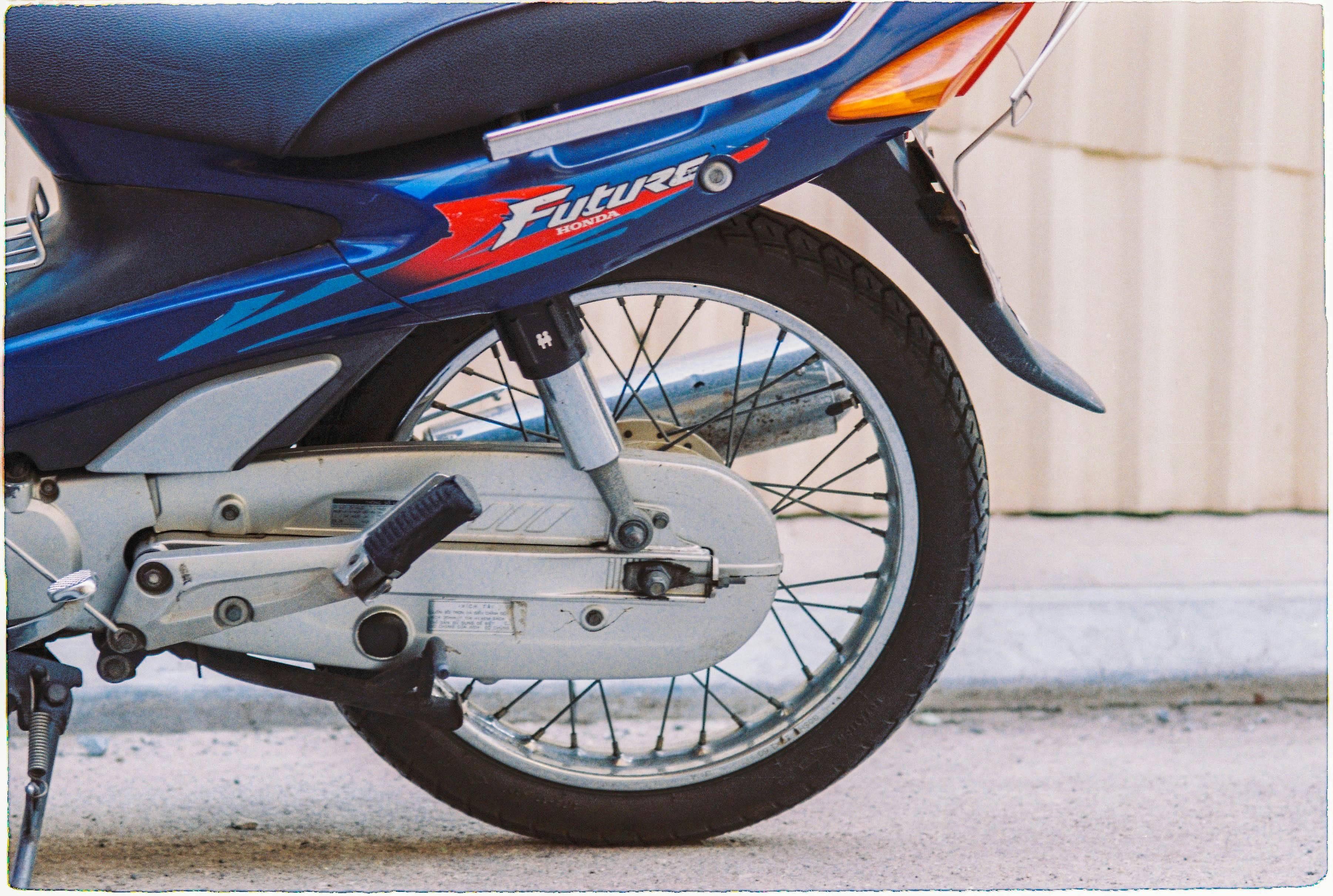 Close-up of a blue motorcycle rear wheel and seat