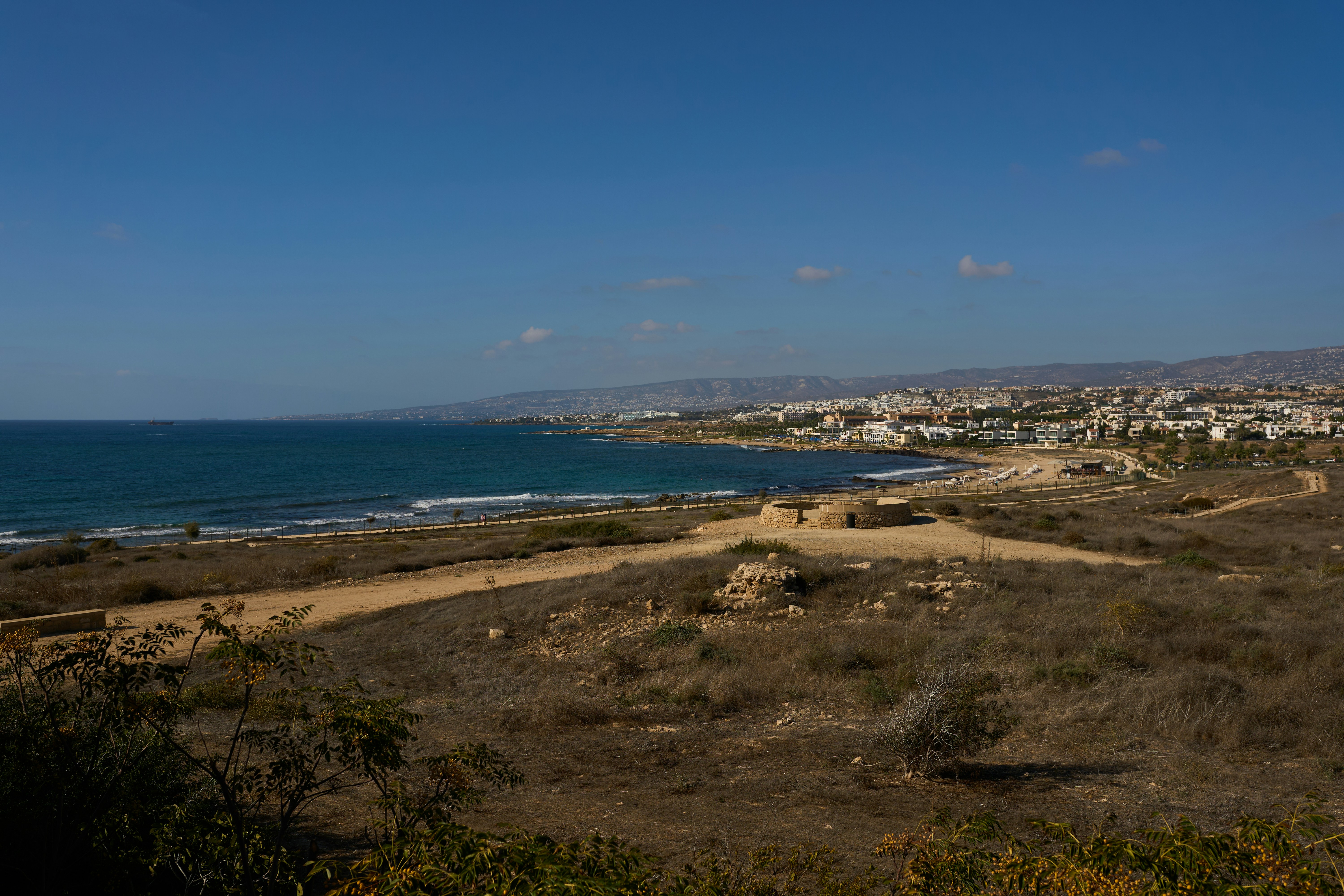 Vast coastal landscape featuring a blend of sandy shores and urban development under a clear blue sky.