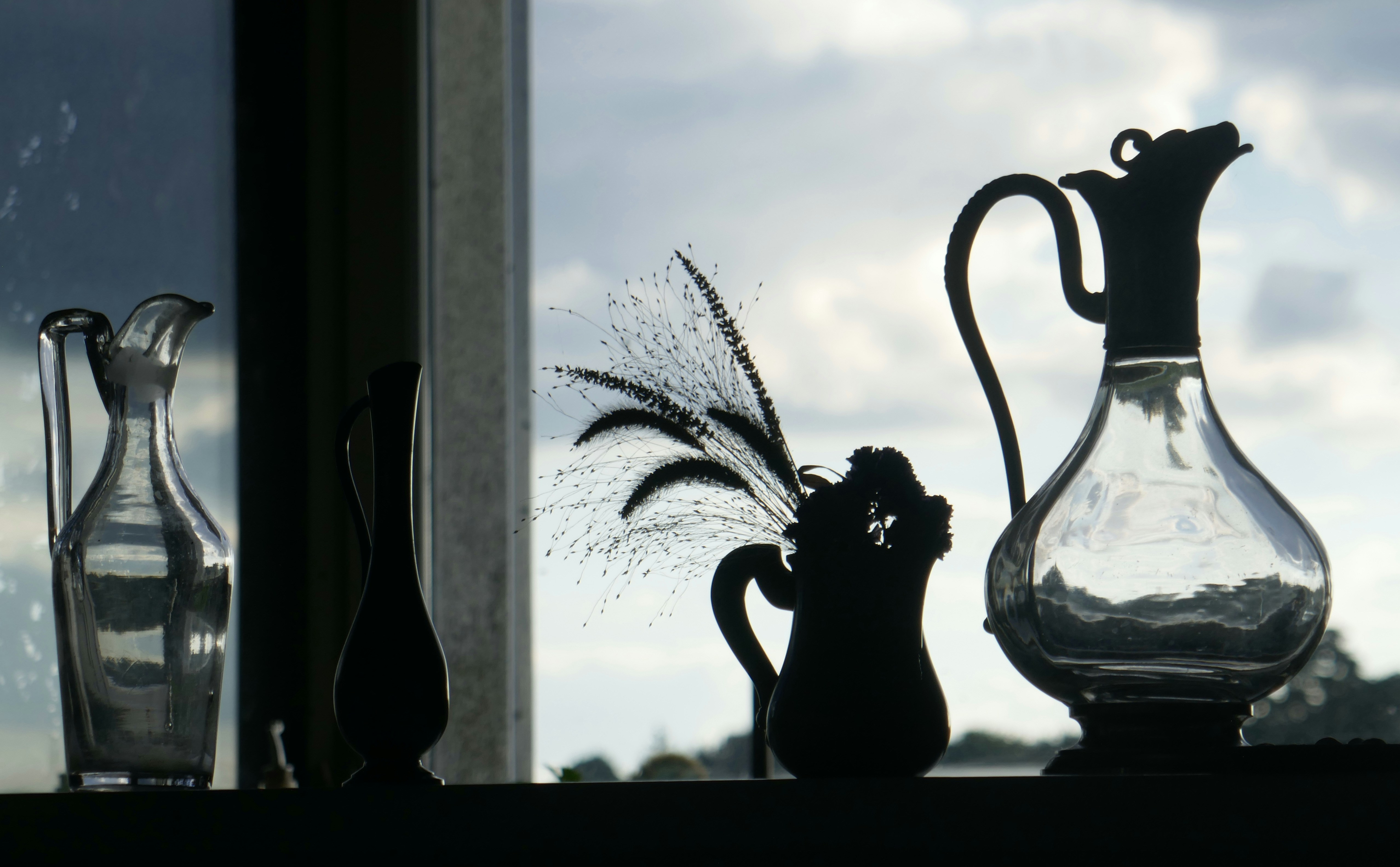 Lumière du soir Rouges Jardins Guy Grandjean | Silhouettes of decorative pitchers and vases by window