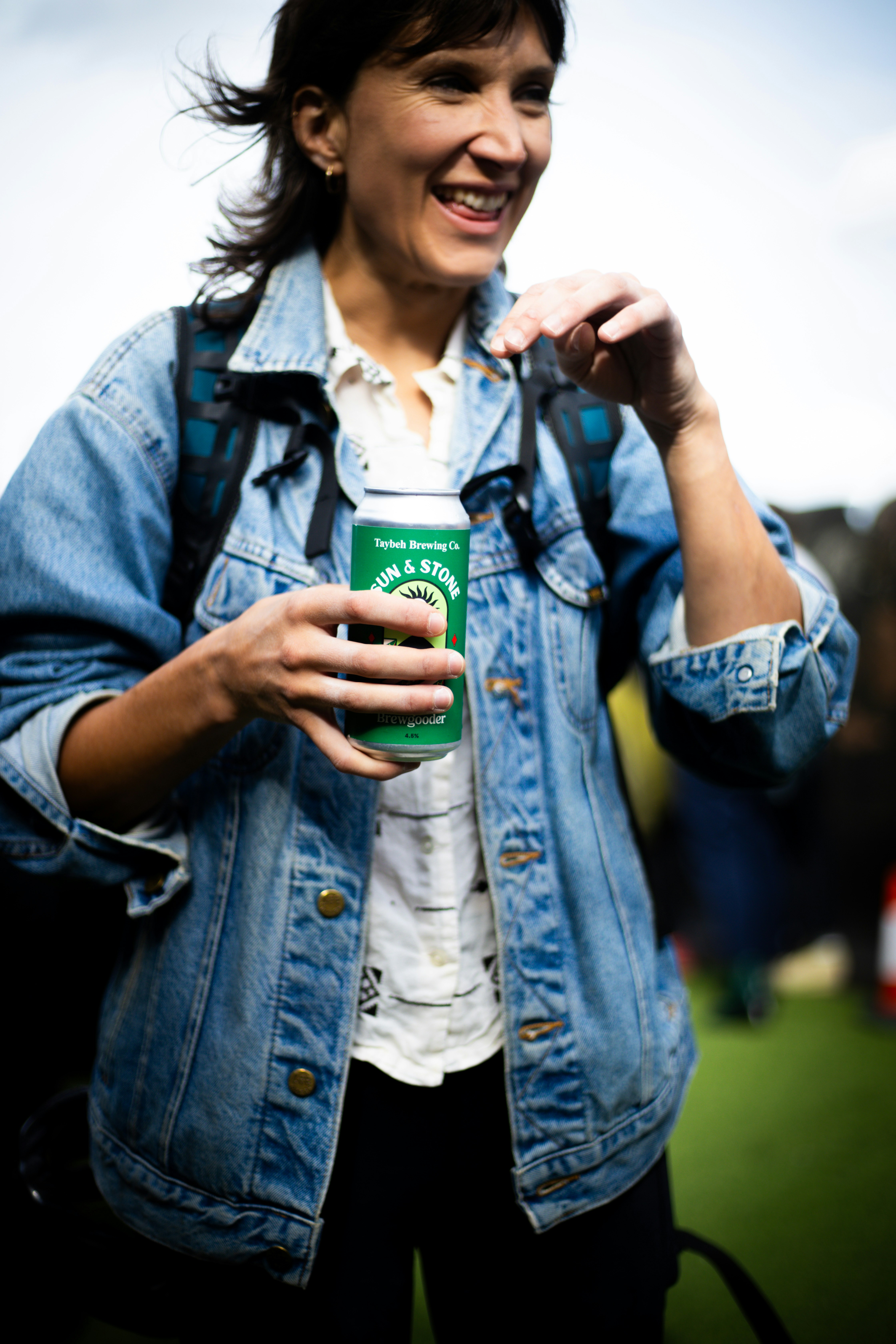 Girl holding beer can | Woman in denim jacket holding a green can