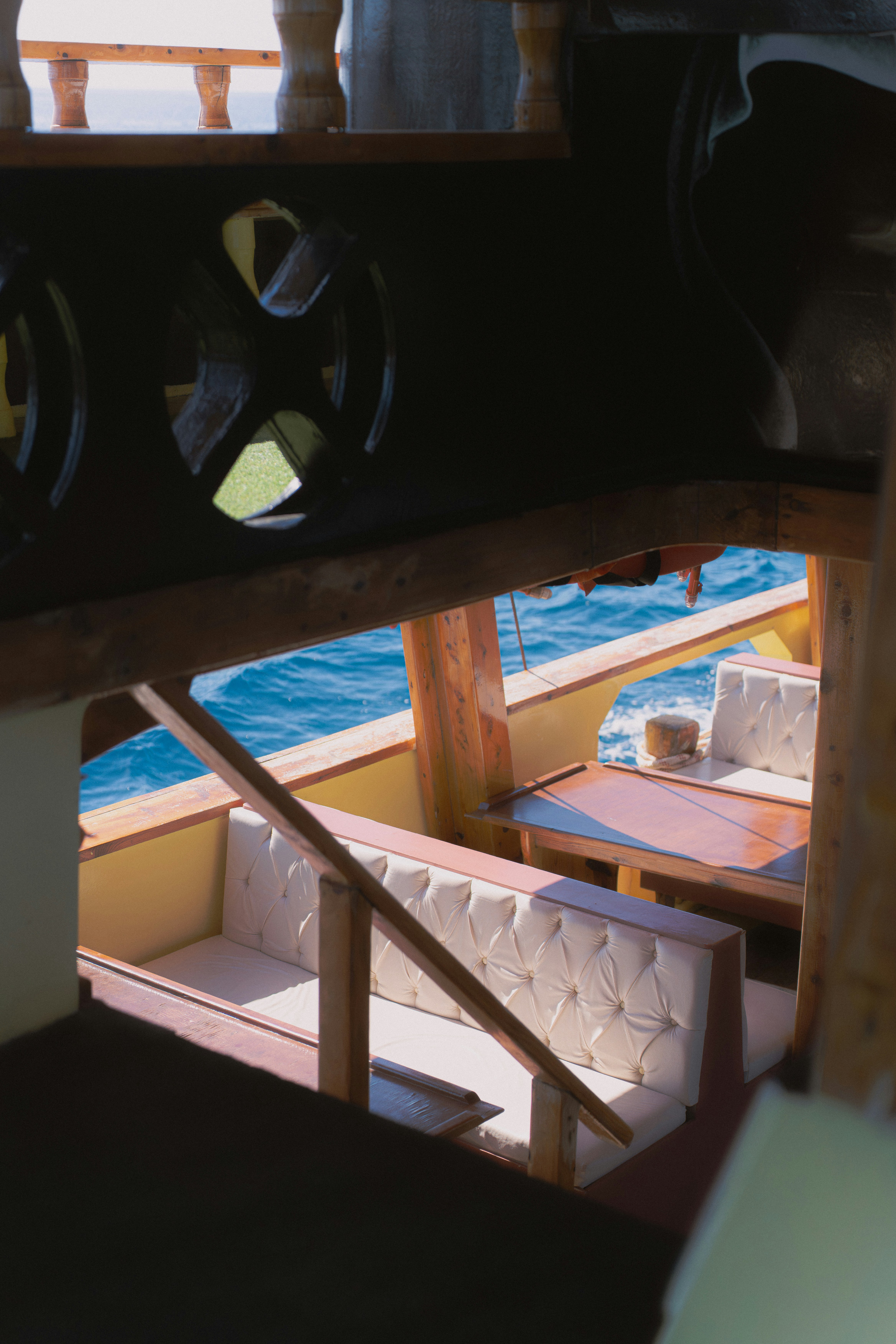 Interior view of a boat showcasing plush seating and wooden accents, with a glimpse of tranquil waters beyond.