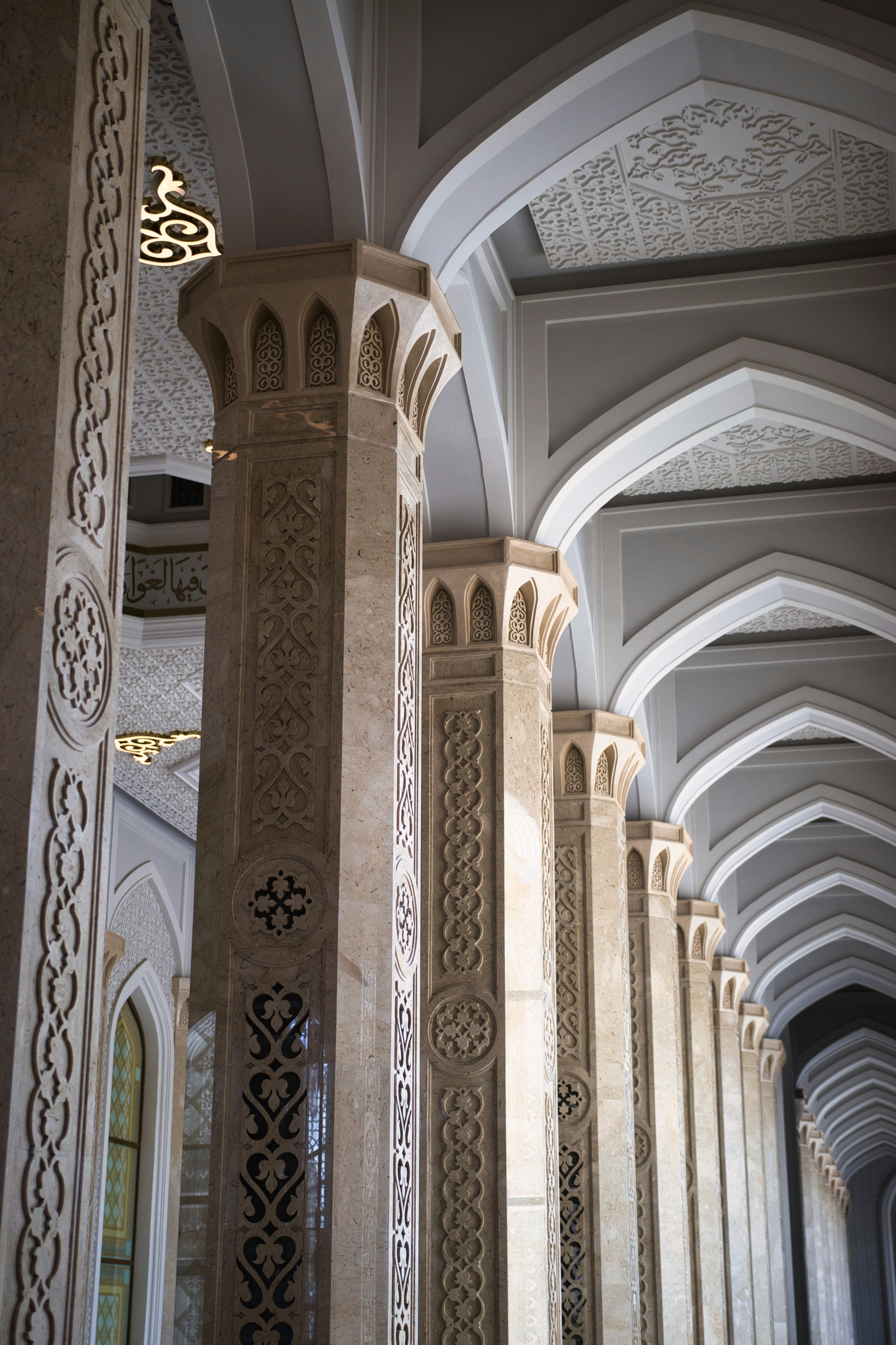 Intricate columns adorned with ornate patterns create a mesmerizing corridor in a grand architectural space.