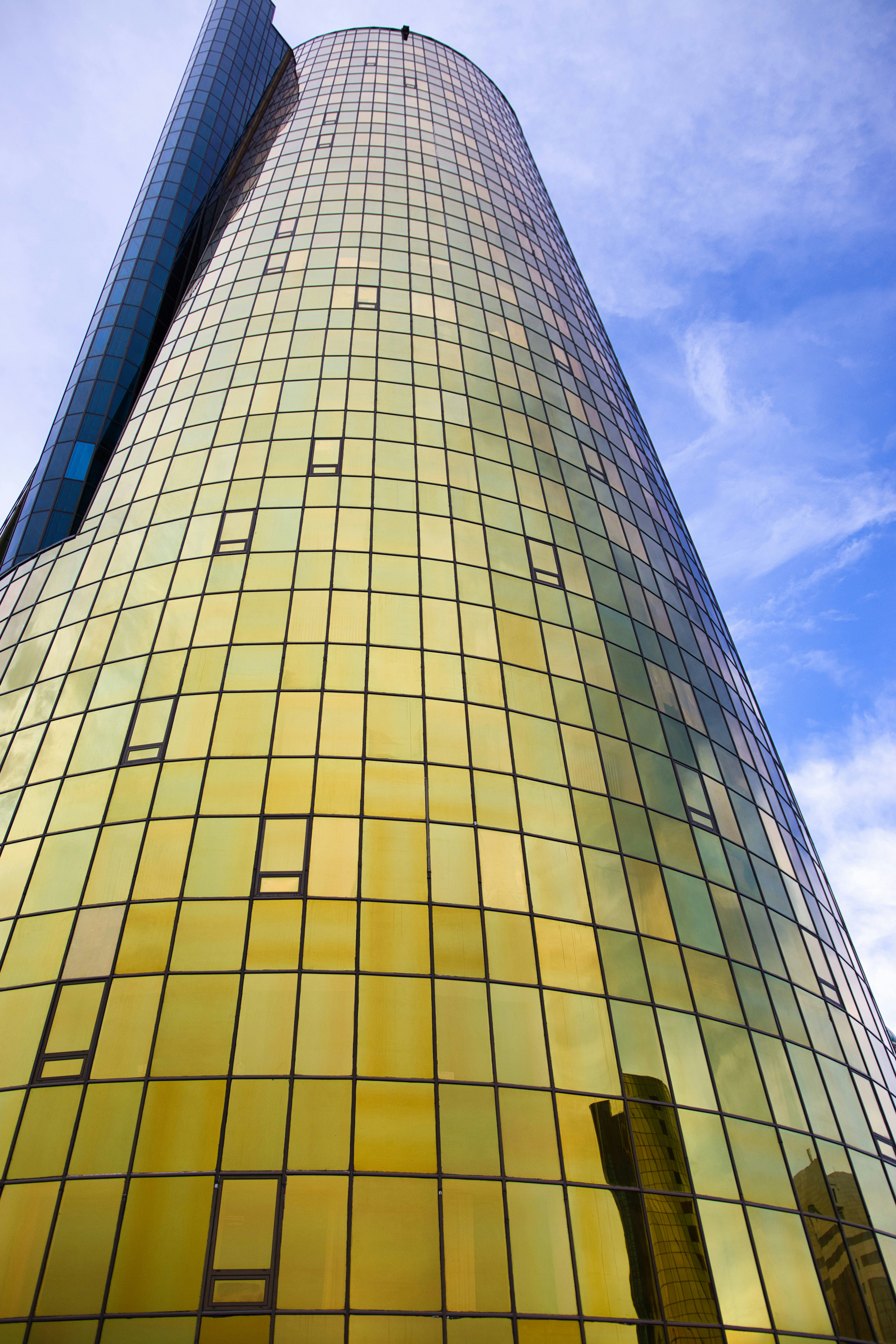 Reflective golden glass facade of a skyscraper under a blue sky, showcasing contemporary design and urban elegance.