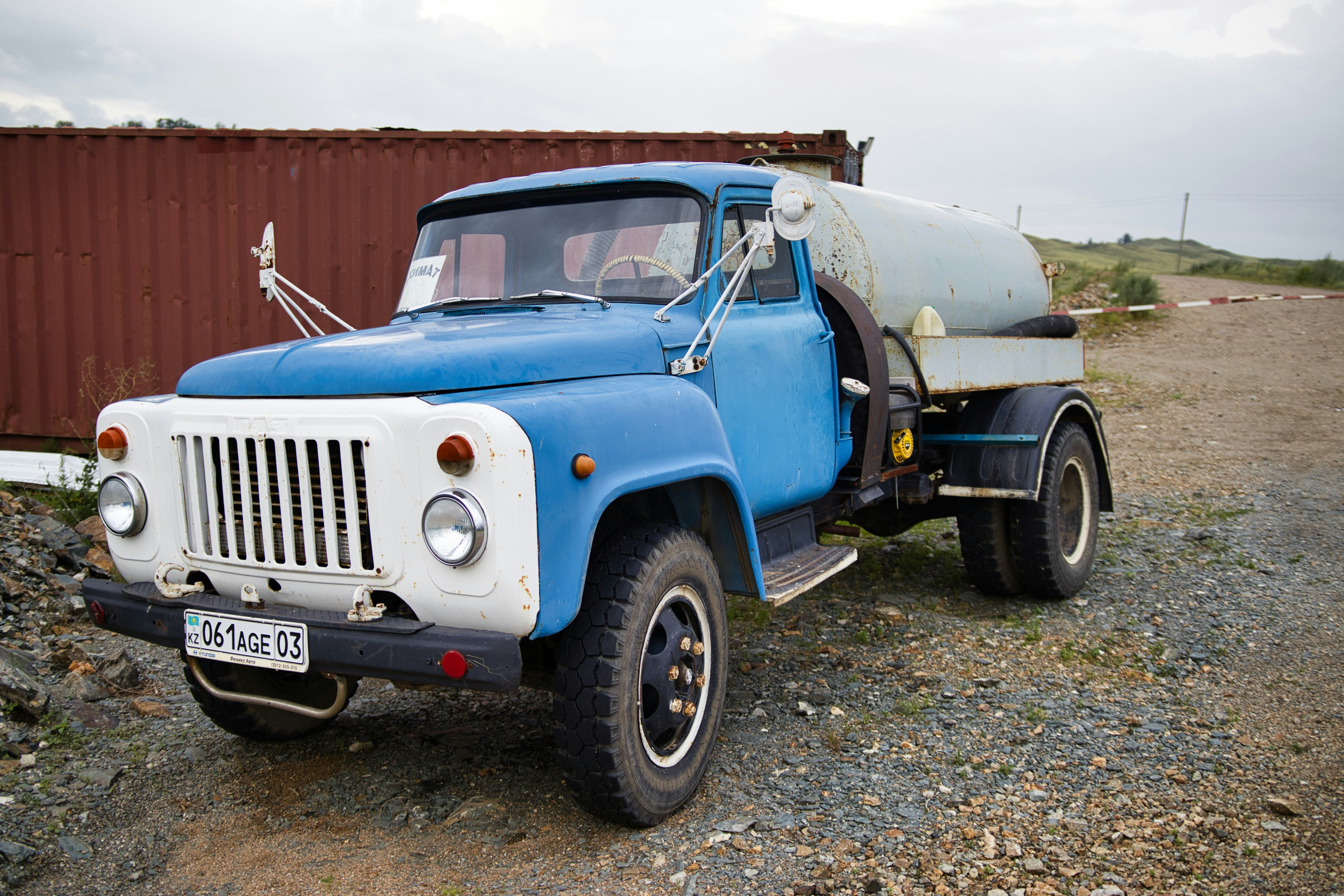 Blue vintage water truck parked on gravel road