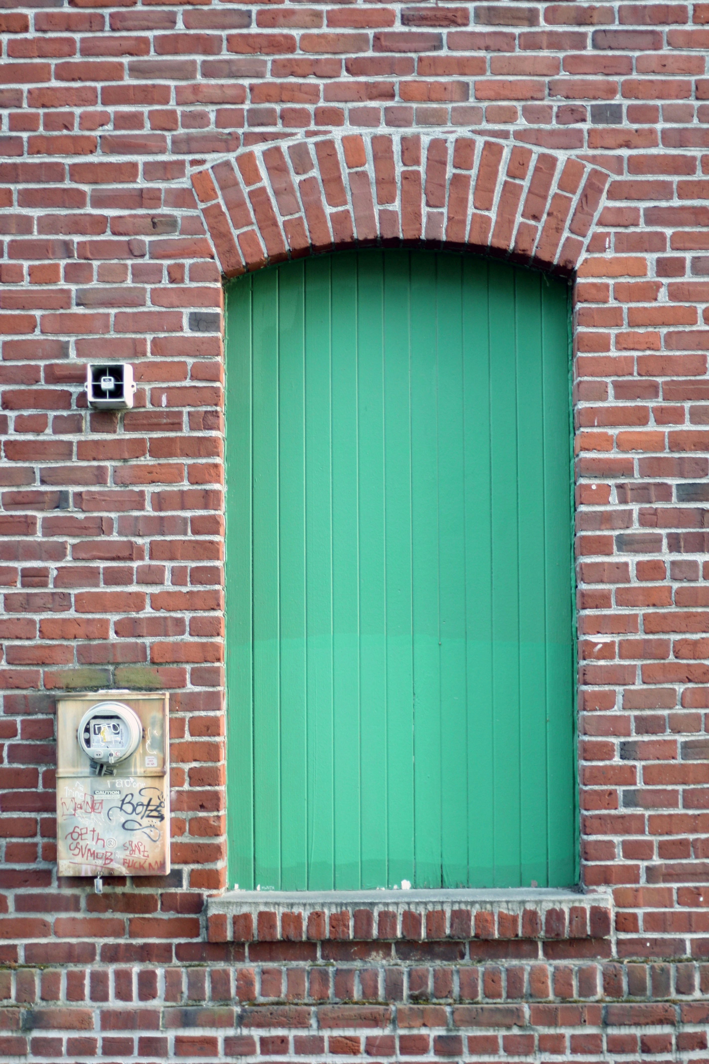 Green shuttered window on a brick wall.