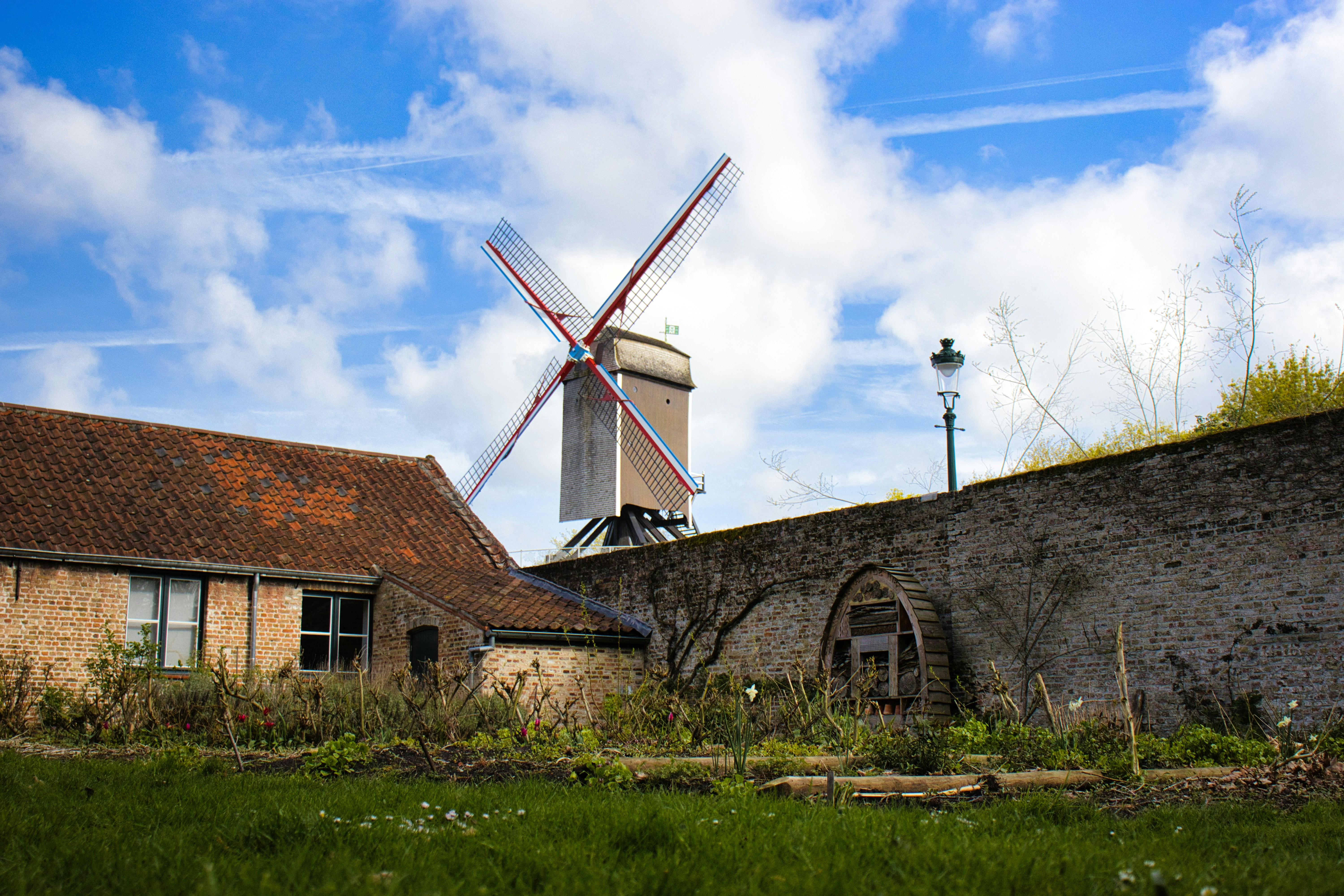 Windmill Above the Wall: A Quiet Countryside Yard Framed by Brick and Stone