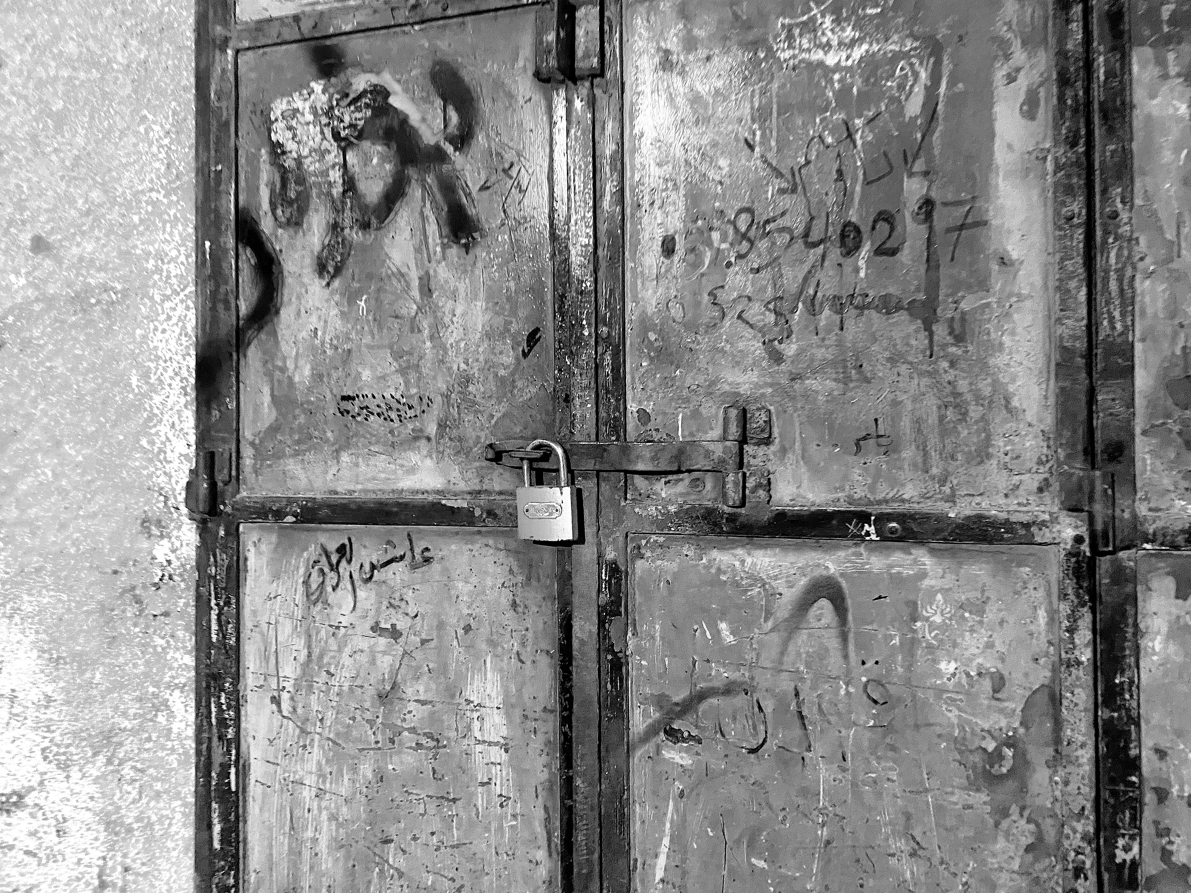 Locked metal doors with graffiti and rust