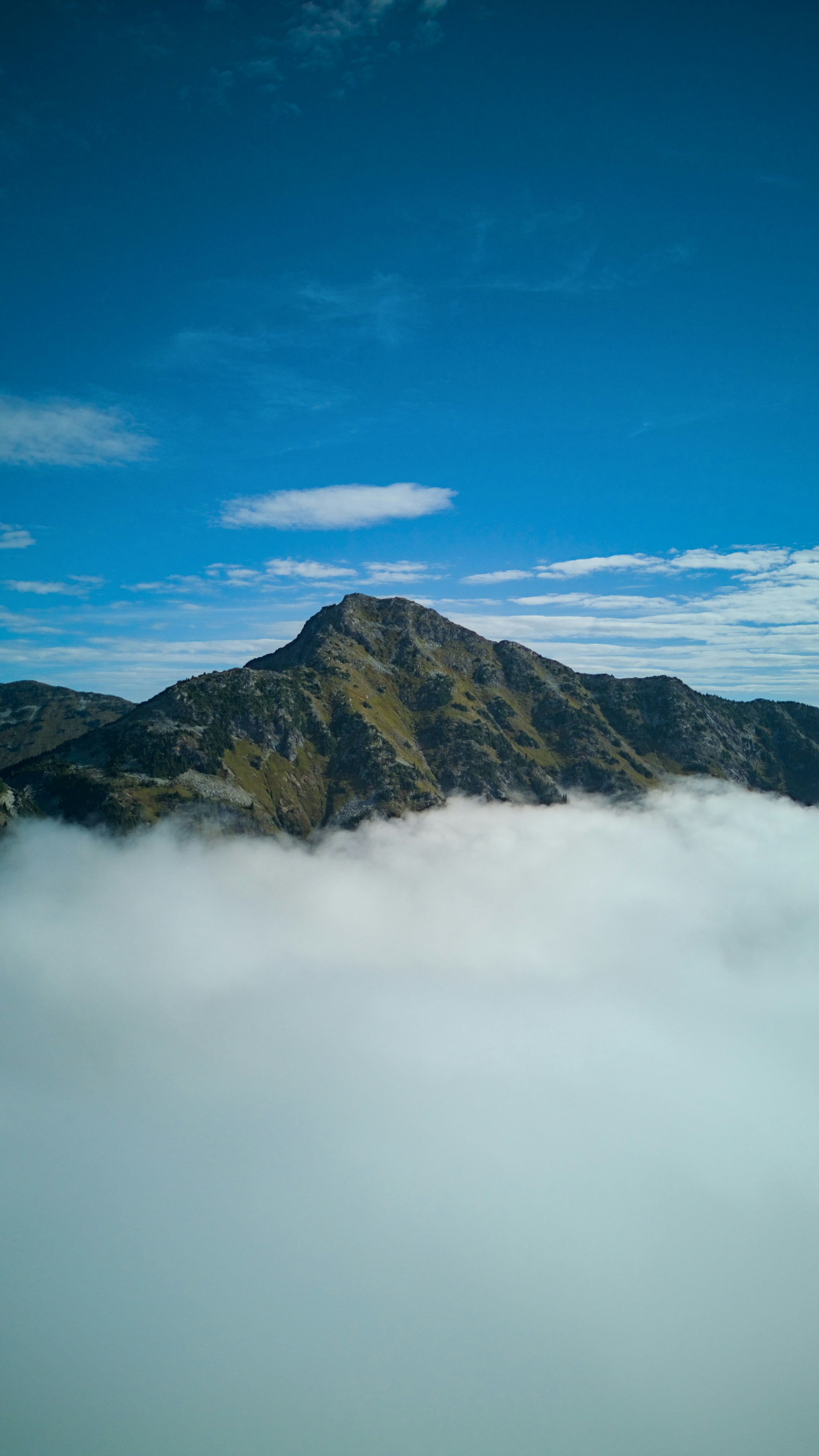 Beautiful view of mountains above the clouds. | Mountain peak emerges from a sea of clouds