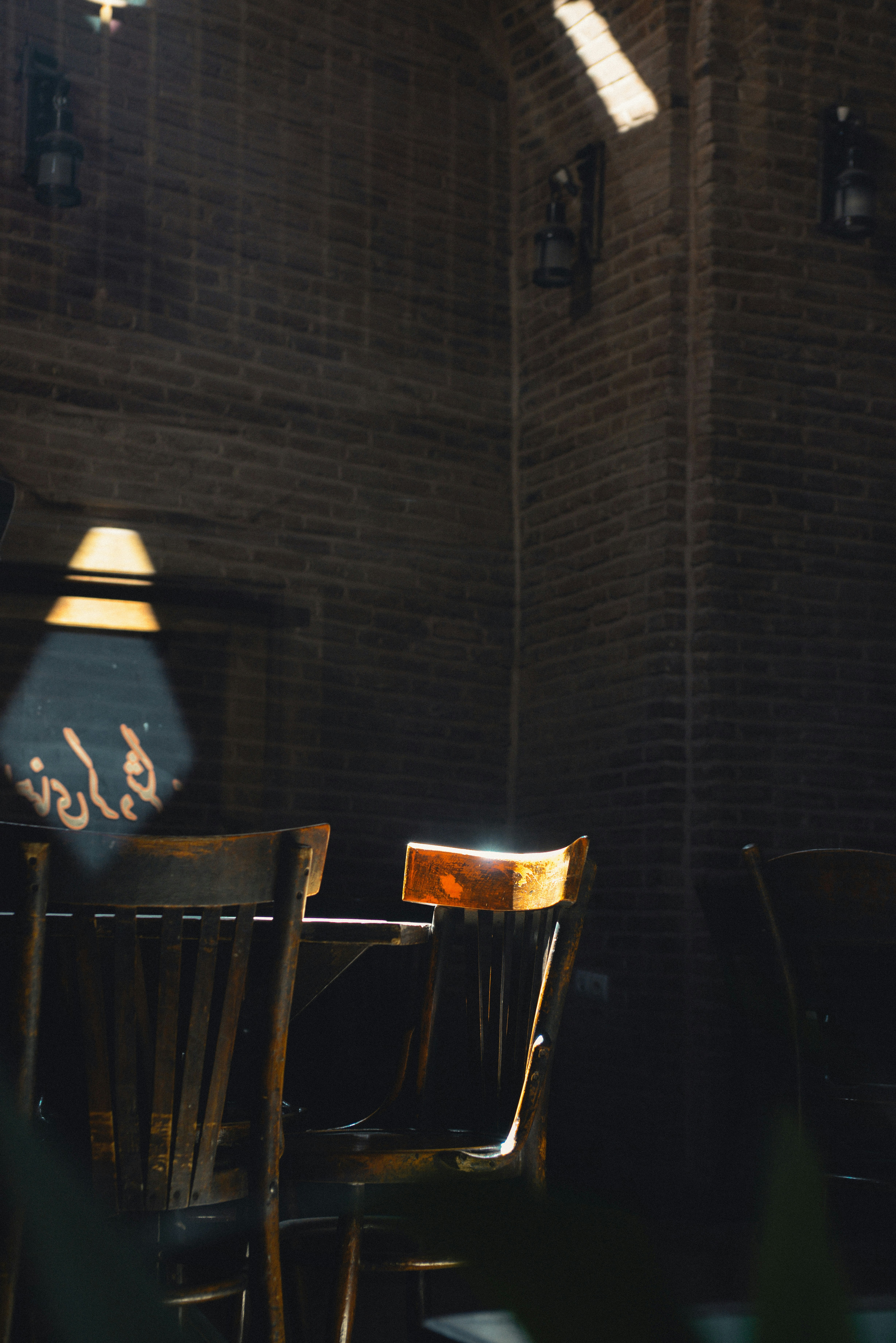 Sunlight streams onto empty wooden chairs in a cafe.