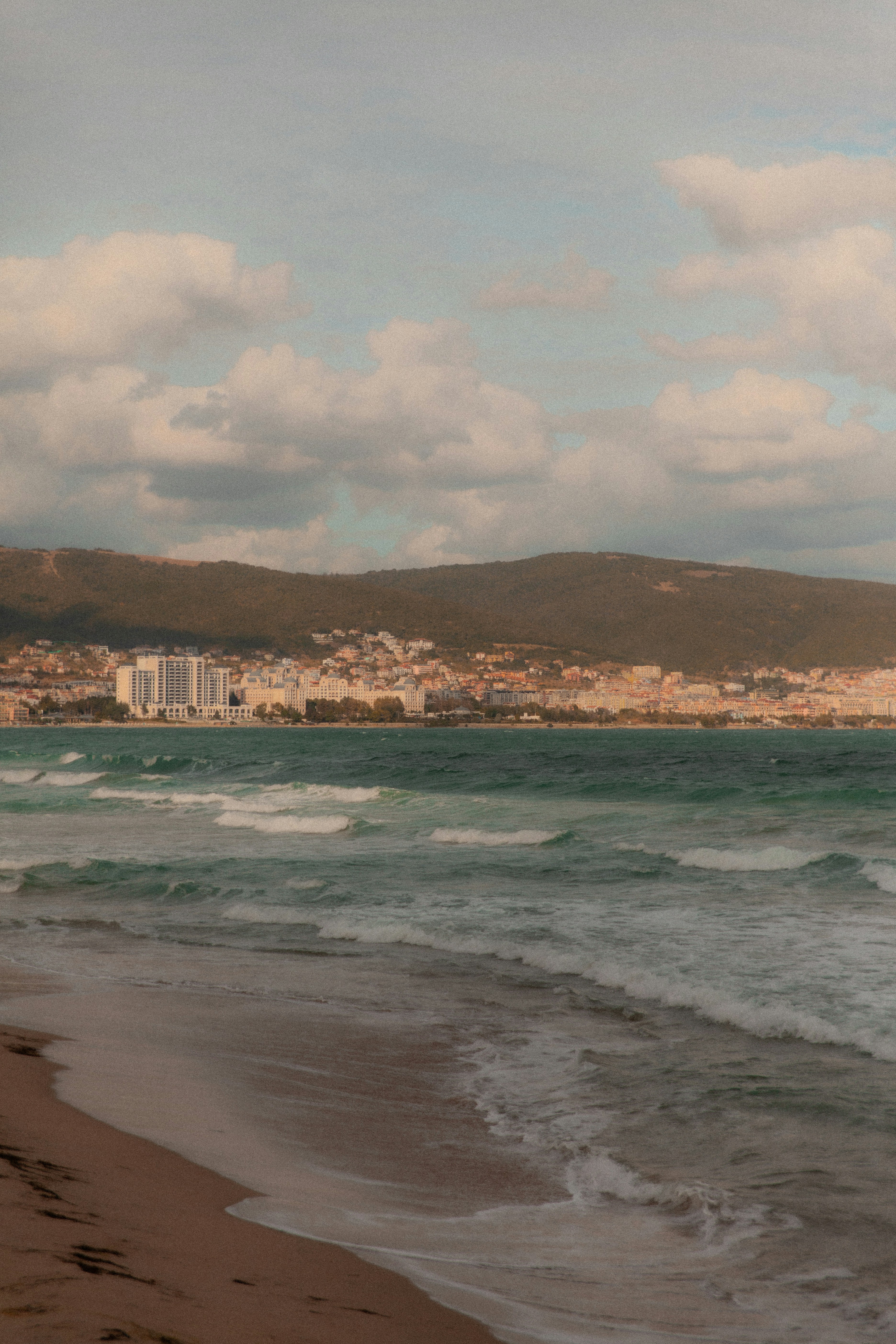 Pastel Seaboard: A Quiet Beach Framing a Hillside City