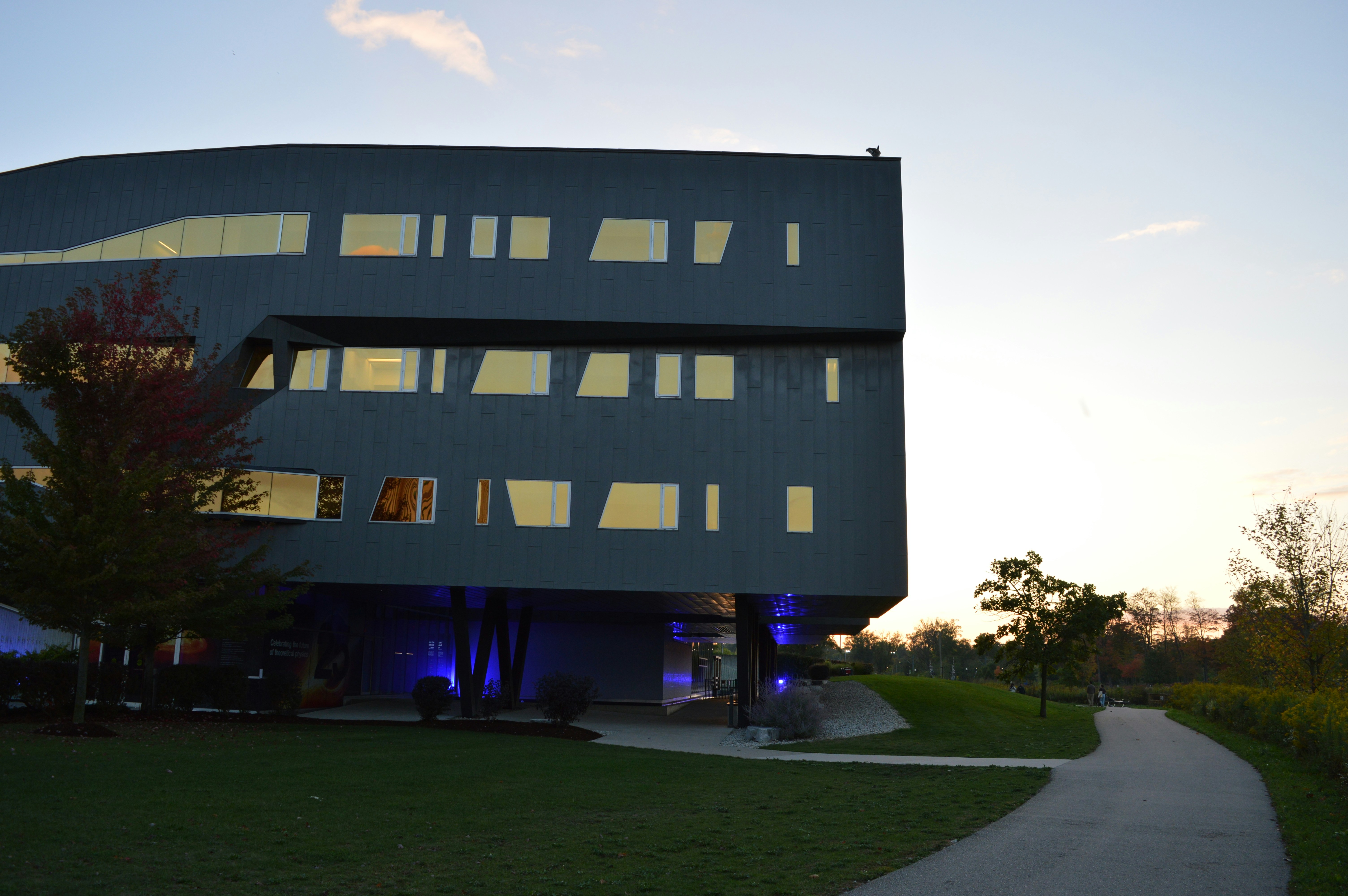 The Perimeter Institute located in Waterloo Park, reflecting it's golden mirrors. | Modern building with blue lights at dusk