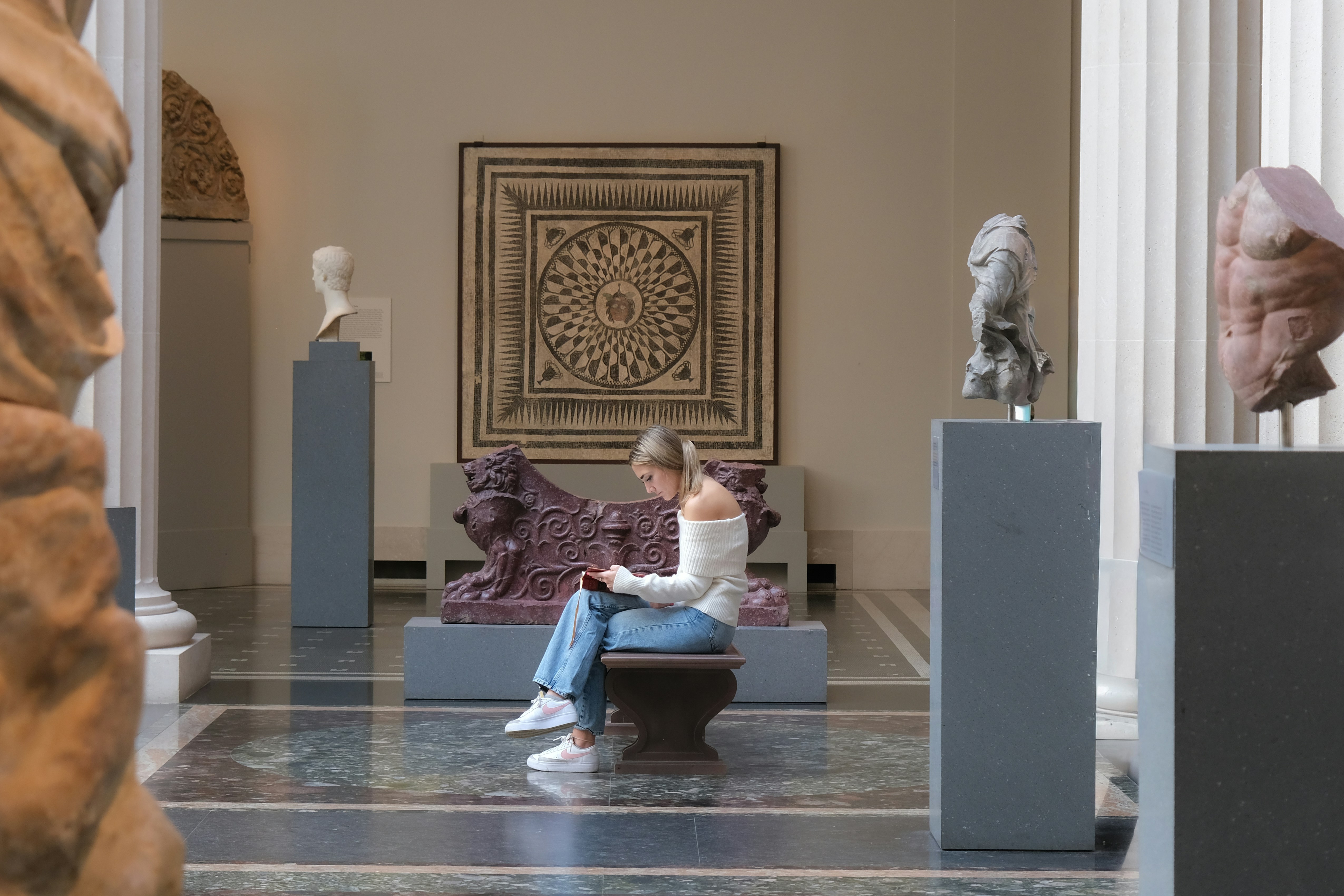 Woman sketching art in a museum gallery hall.