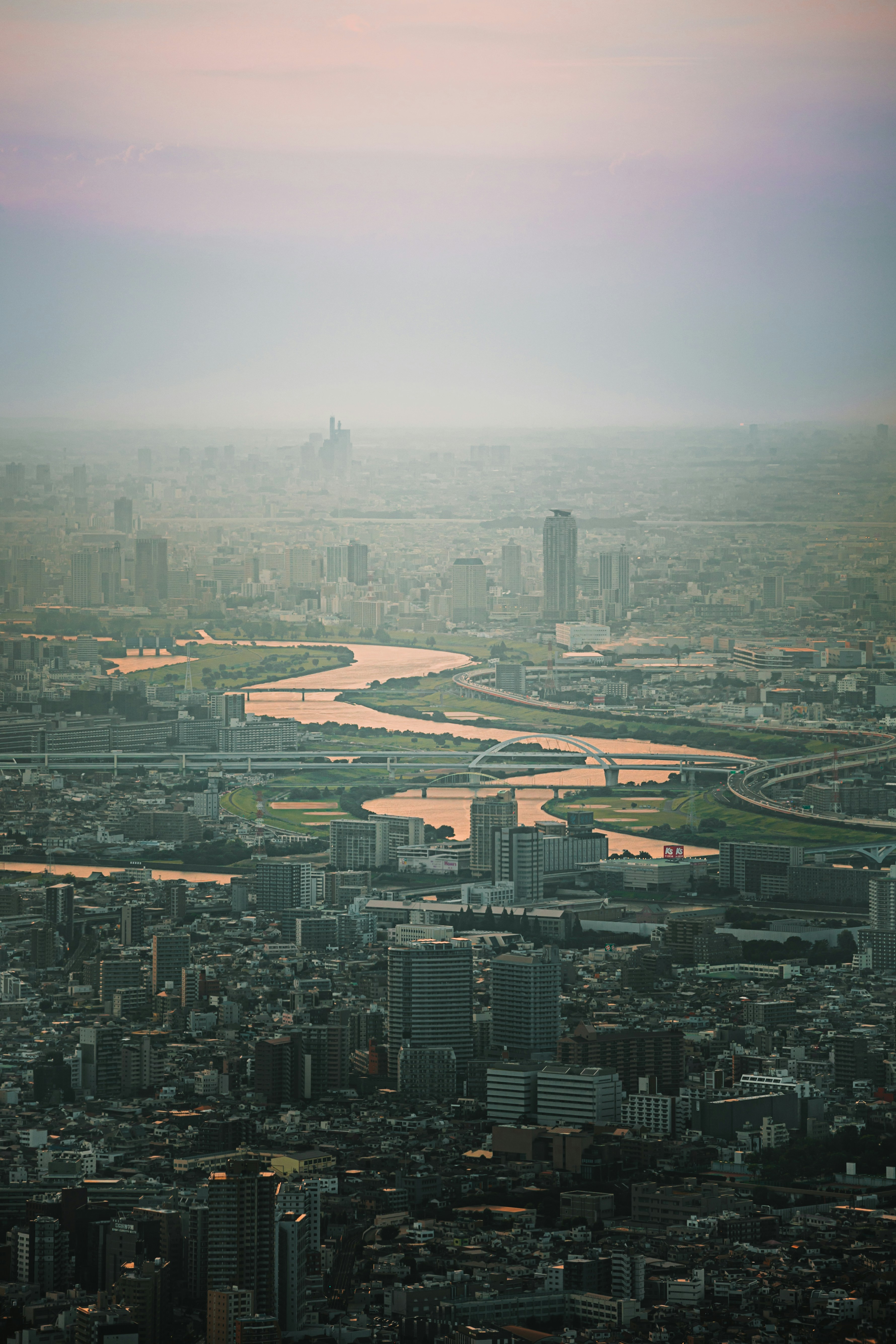 Misty cityscape with a winding river at sunset.