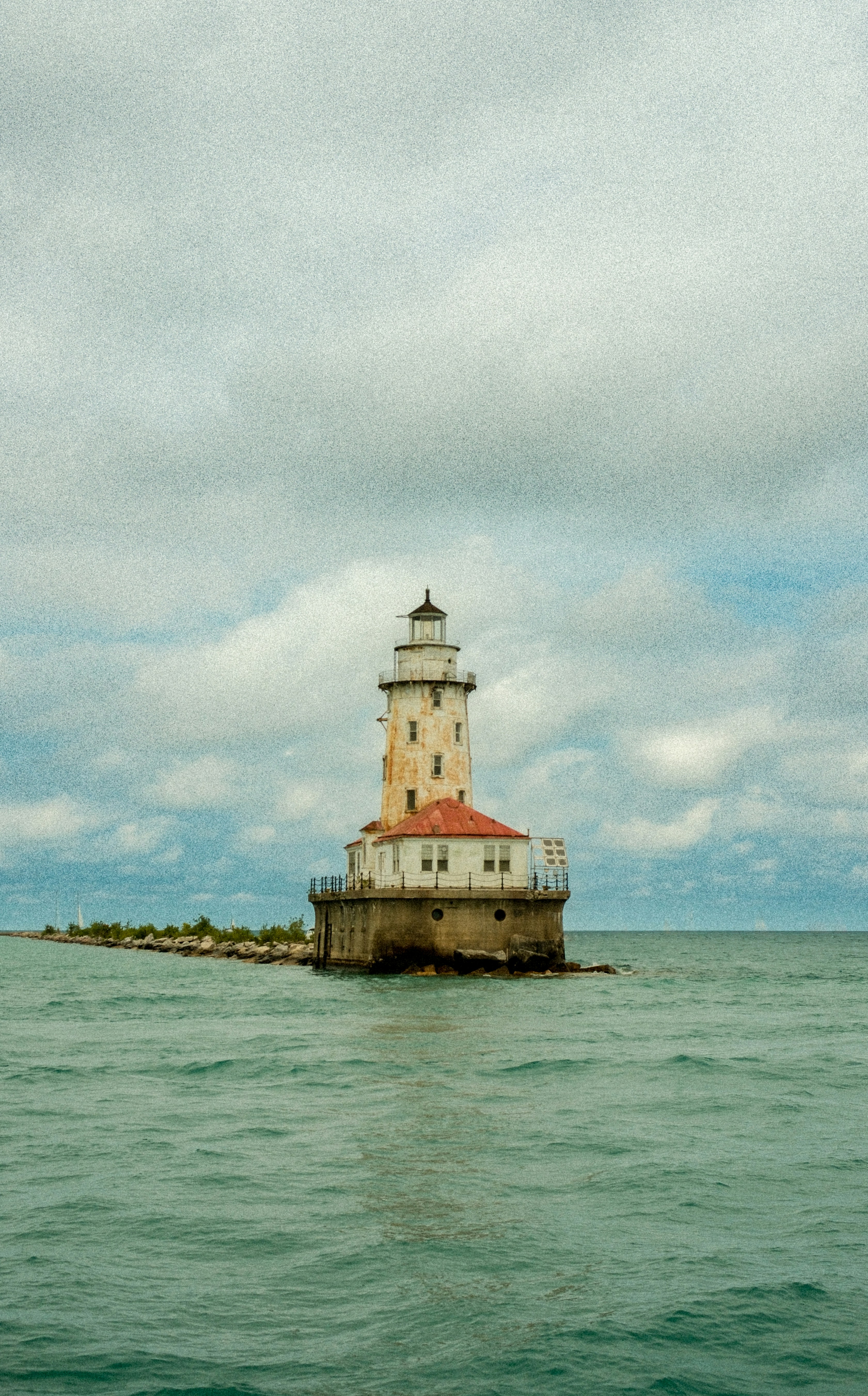 A lone lighthouse in the middle of a lake | A lighthouse stands on a small island in the sea.