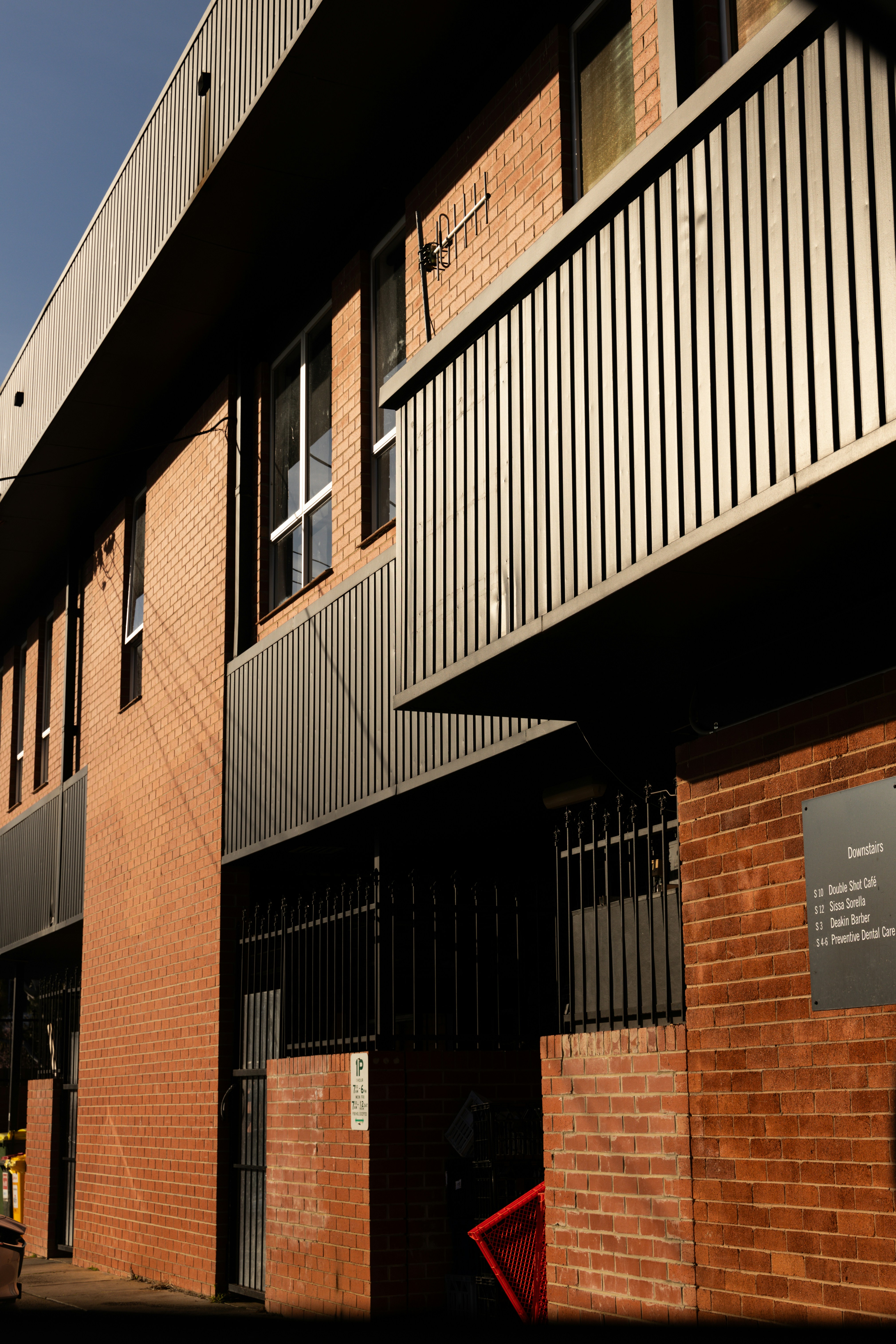 Modern architectural facade featuring a blend of brick and metal elements under bright sunlight.