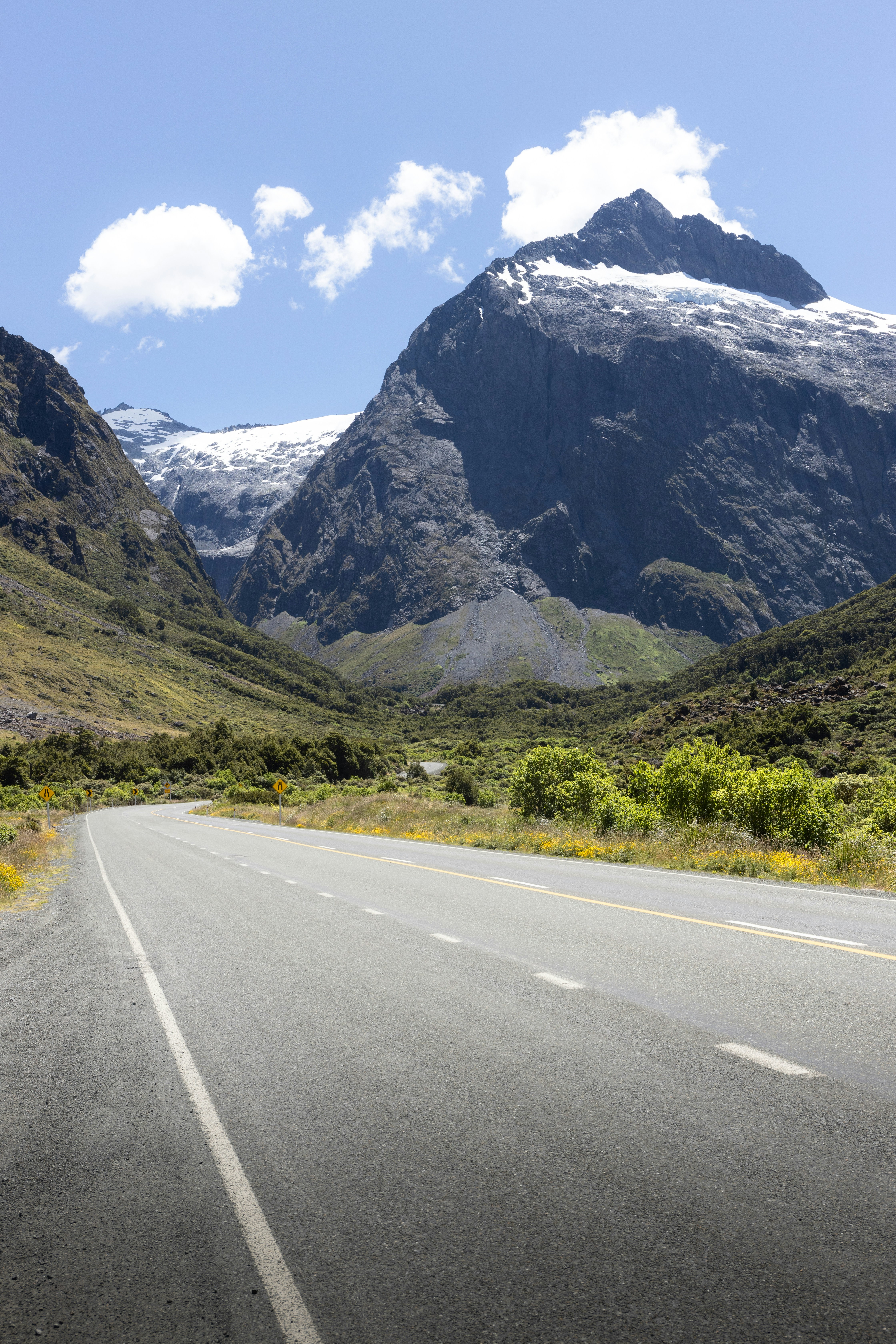 Path to Milford Sound | A winding road leads to a majestic snow-capped mountain.