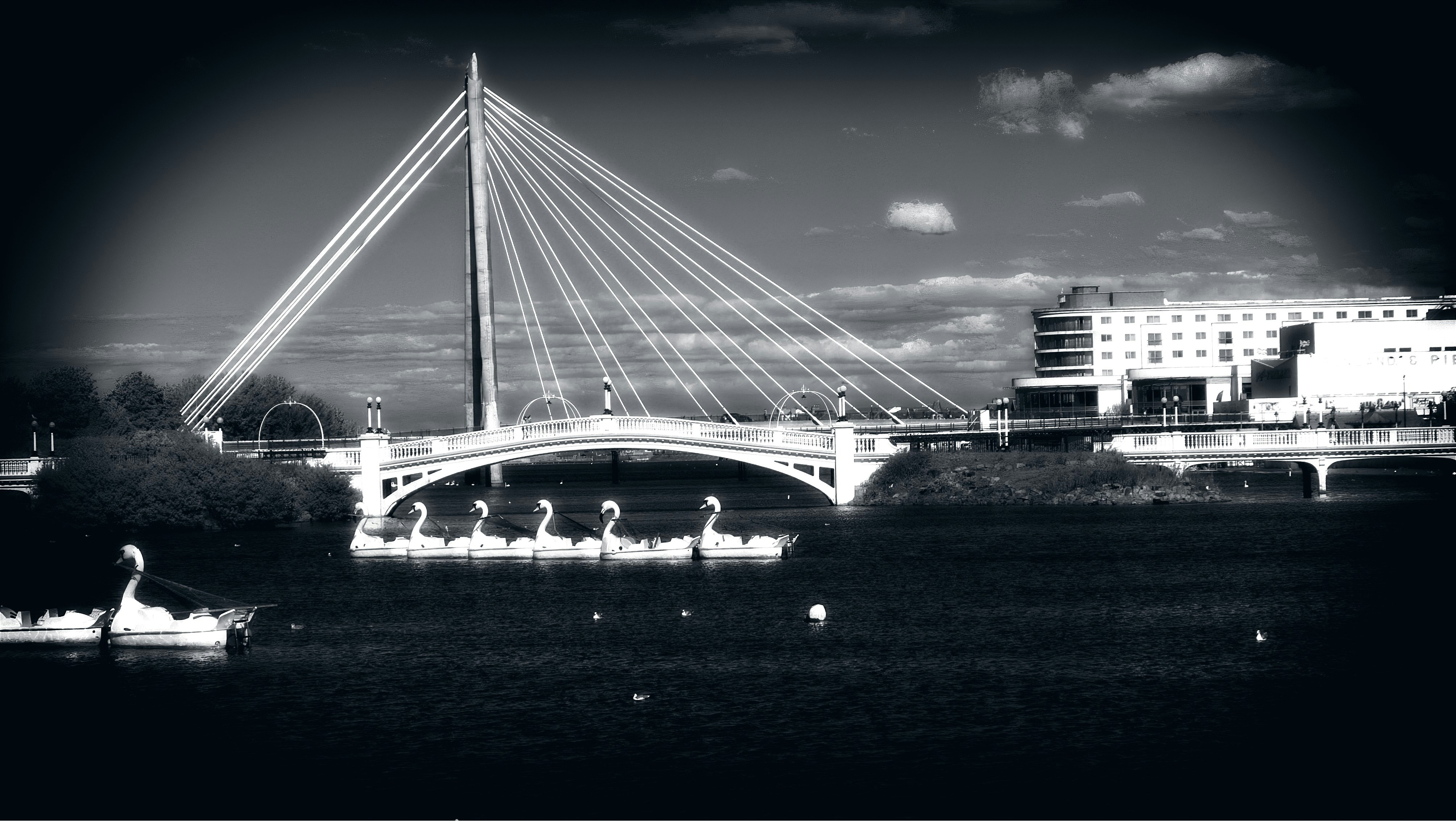 A photo walk through the historic Victorian gardens in Southport England. Images taken with a LUMIX G10 converted to full spectrum infrared. | Swan-shaped boats on a lake with a modern bridge.