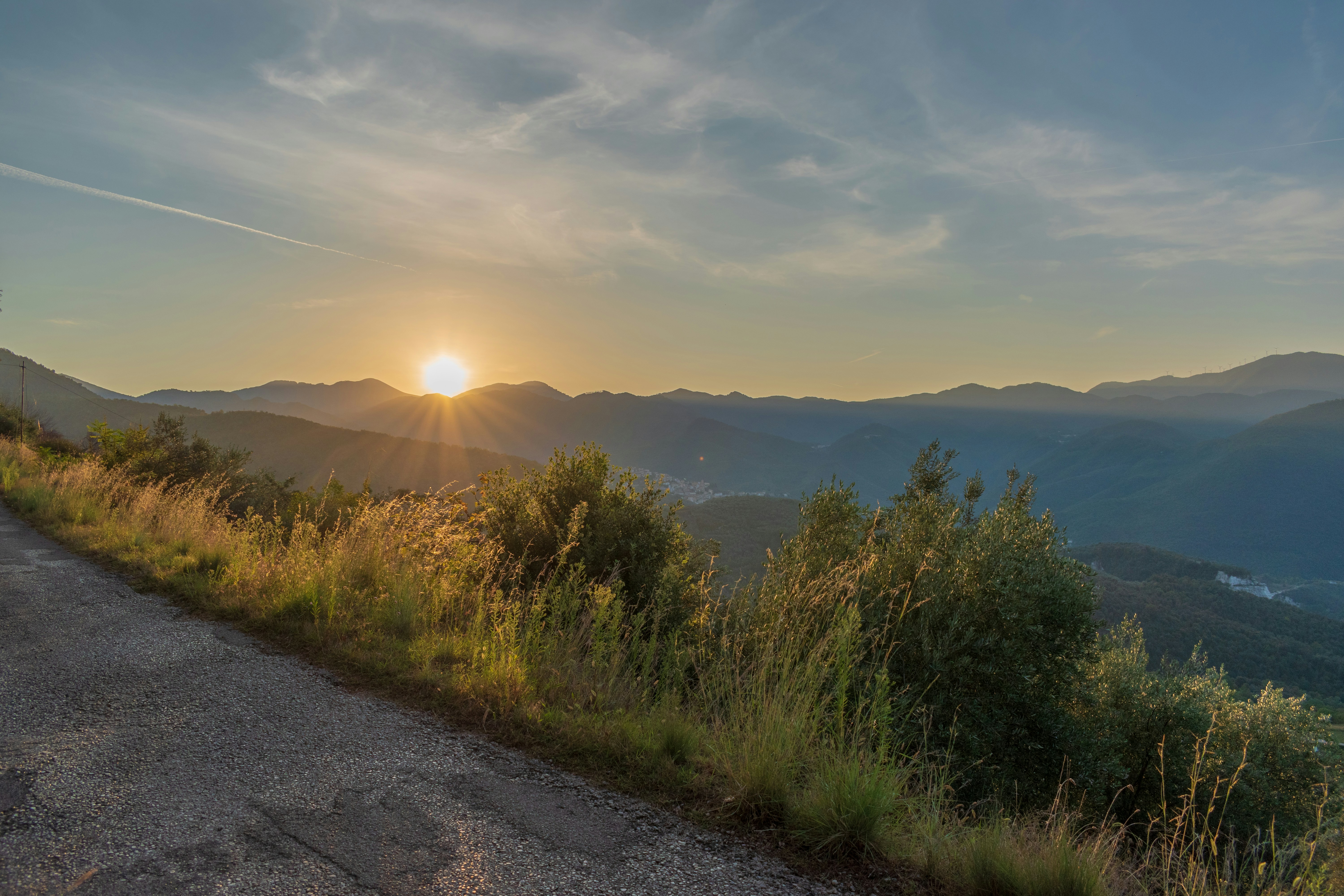 Sunrise over rolling hills with a dirt road.