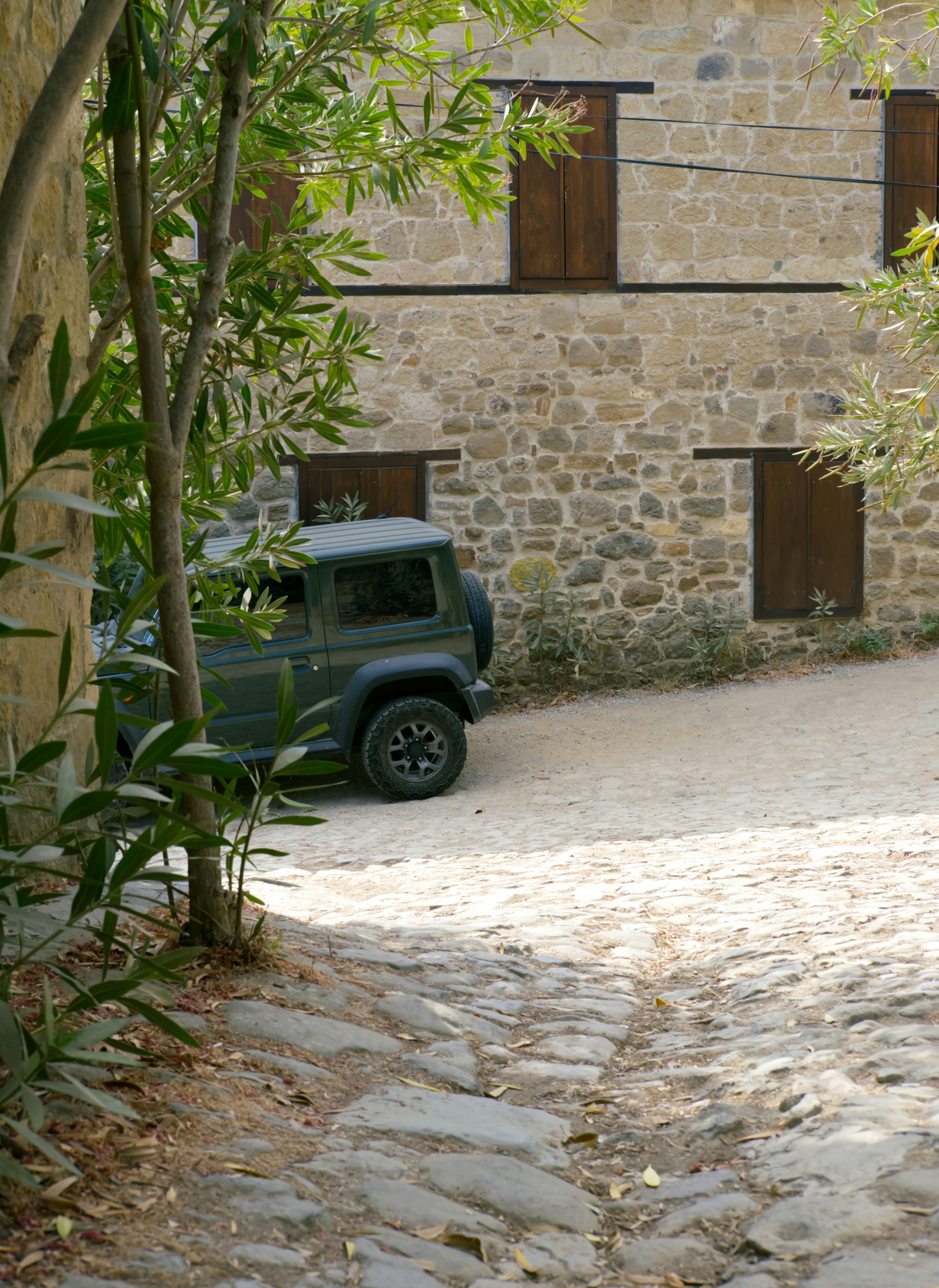 Green Jeep Quietly Anchored by a Rustic Stone House