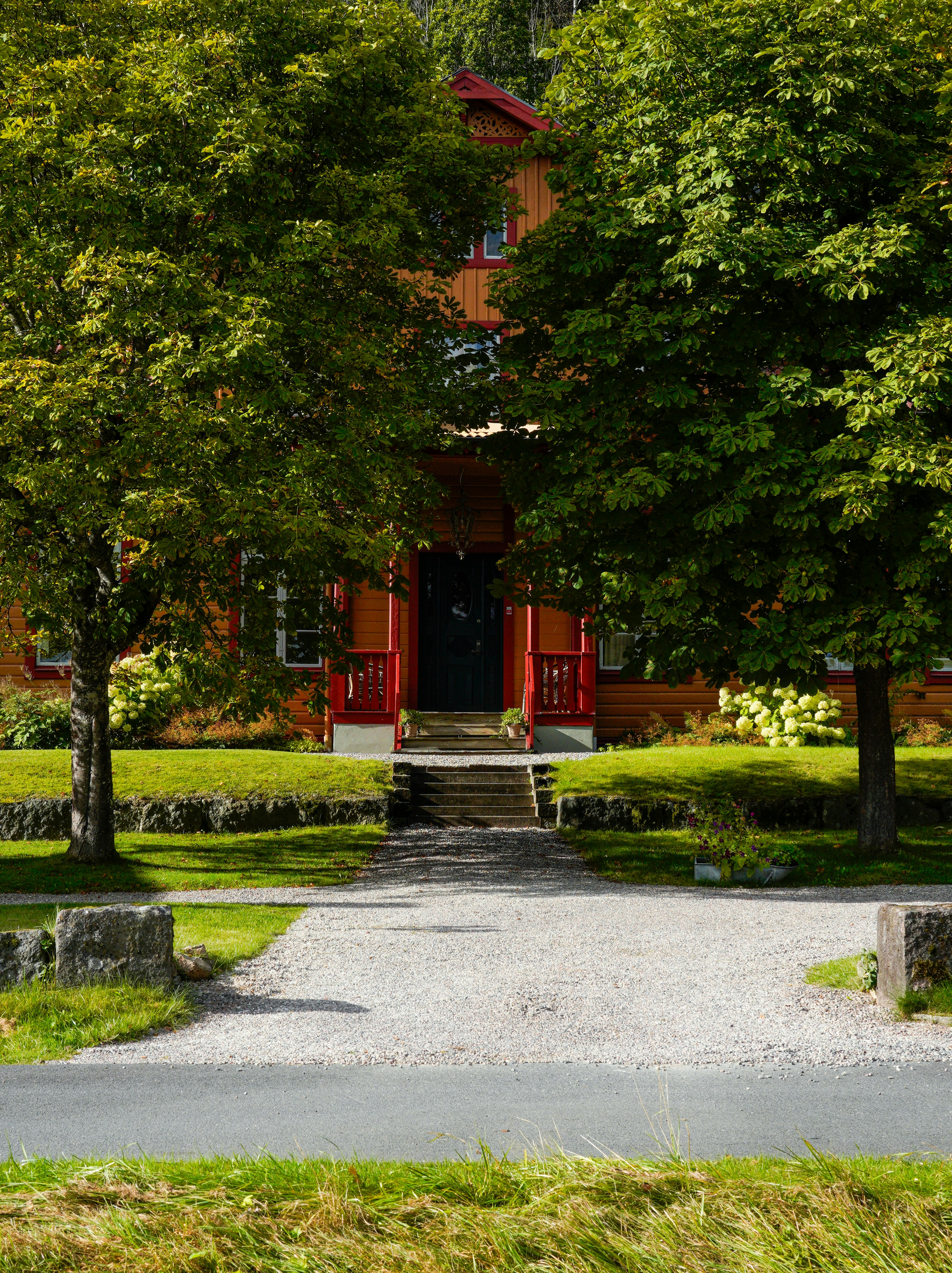 Orange wooden house with red trim and trees