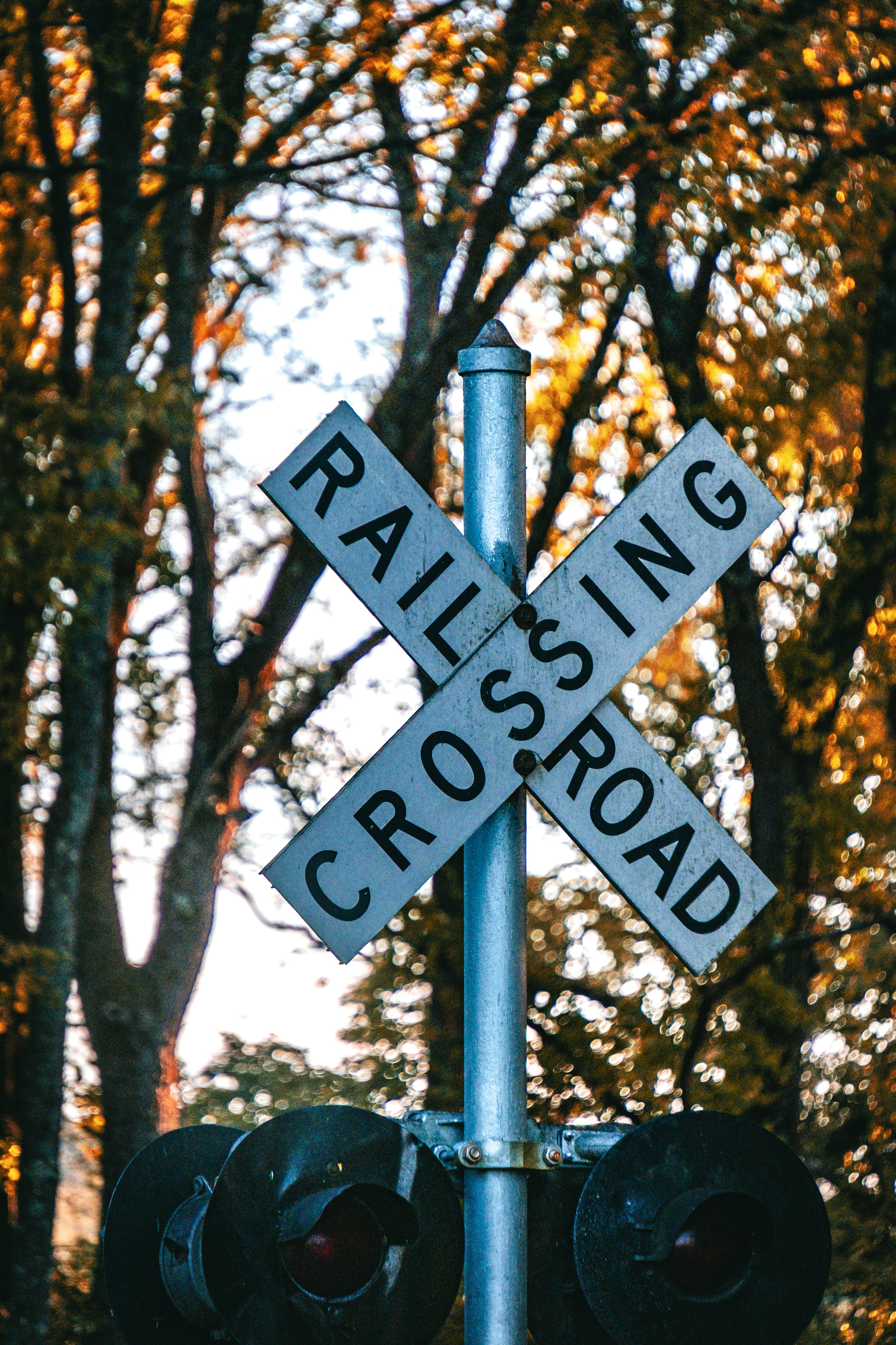 railroad crossing sign with trees in background | Railroad crossing sign with trees in background