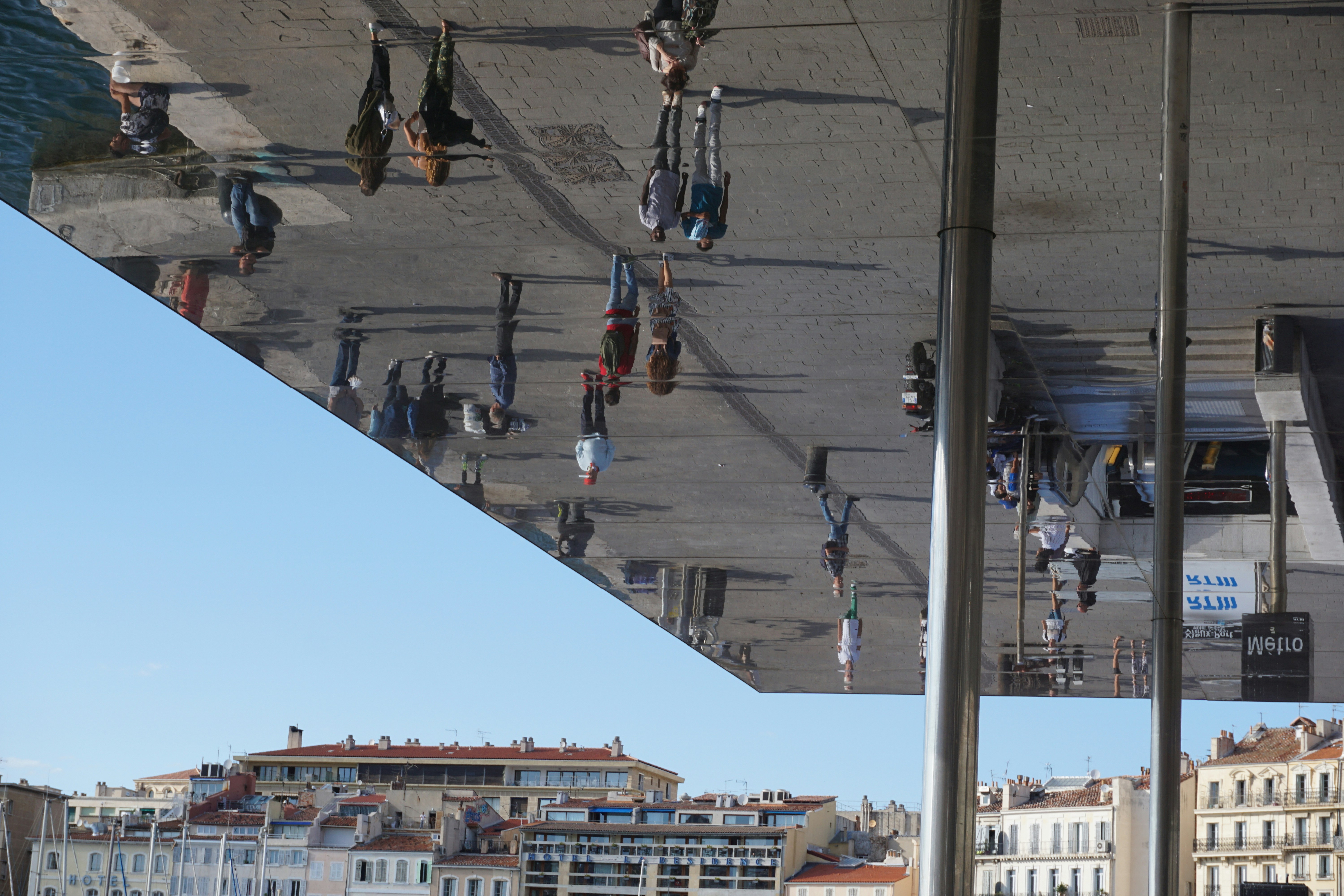 Mirrored Street: Inverted Pedestrians Over a Sunlit Cityscape