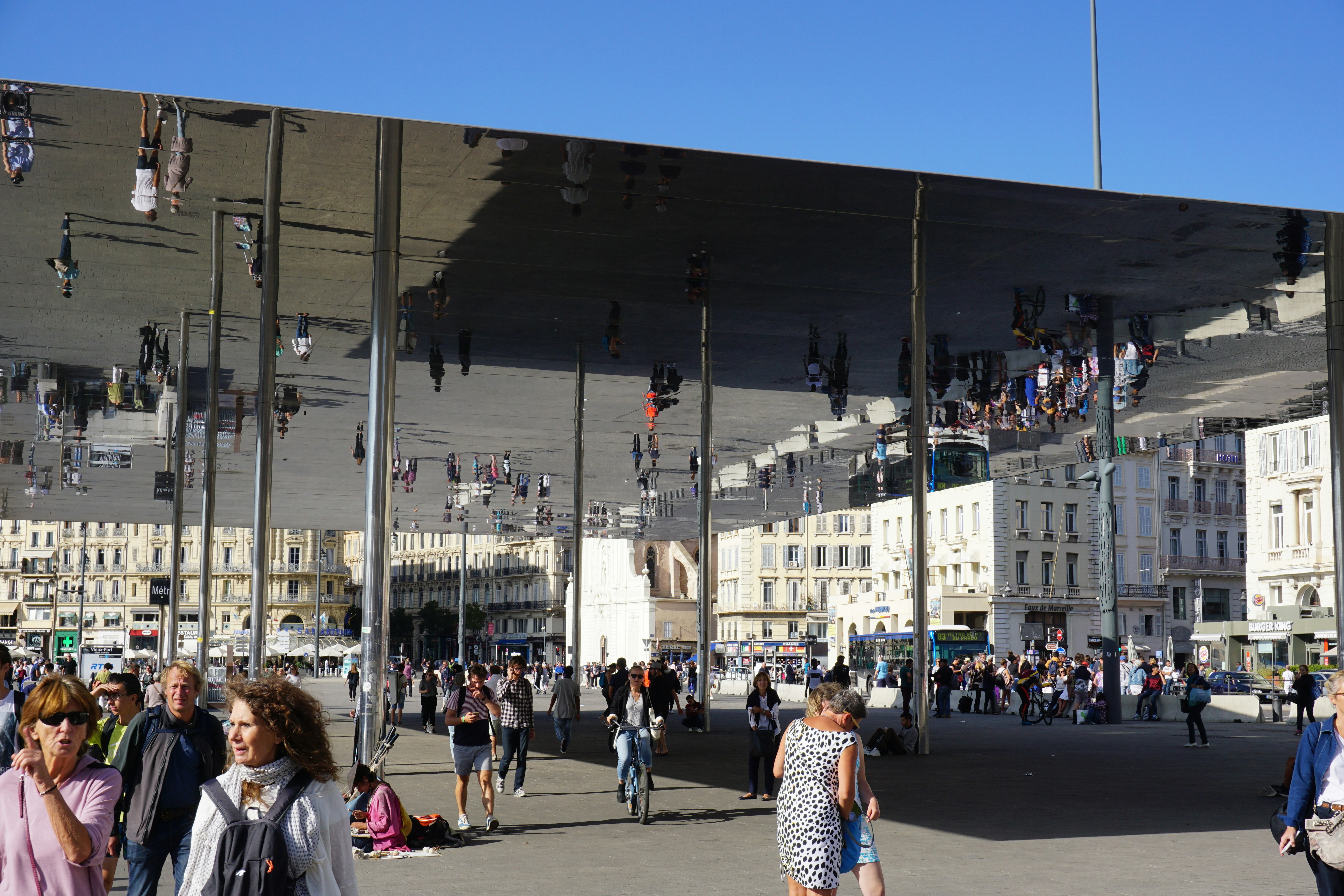 Mirrored Canopy Cityscape: People and Light in a Sunlit Square
