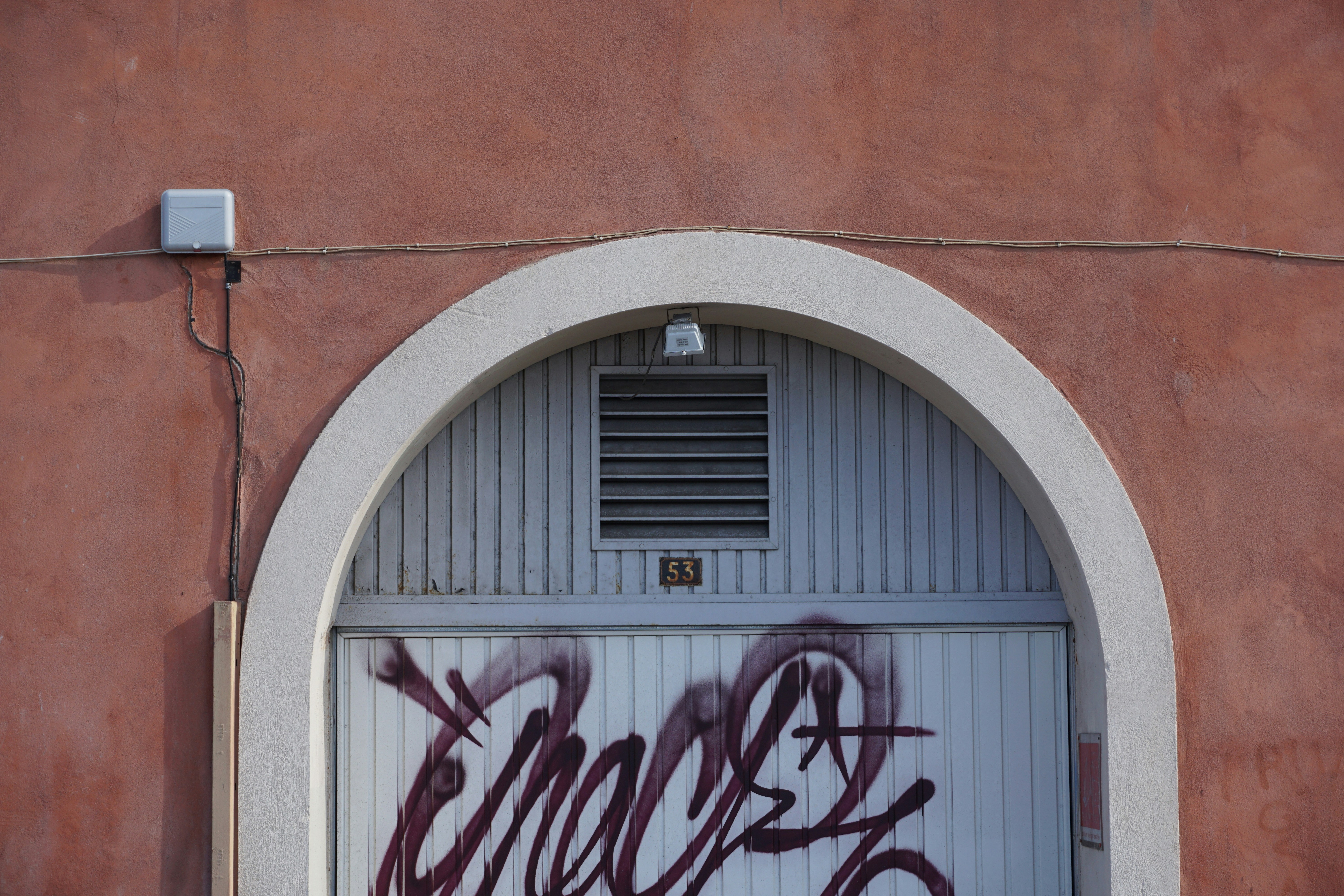 Graffiti covers a closed garage door under an arch. photo – Free ...