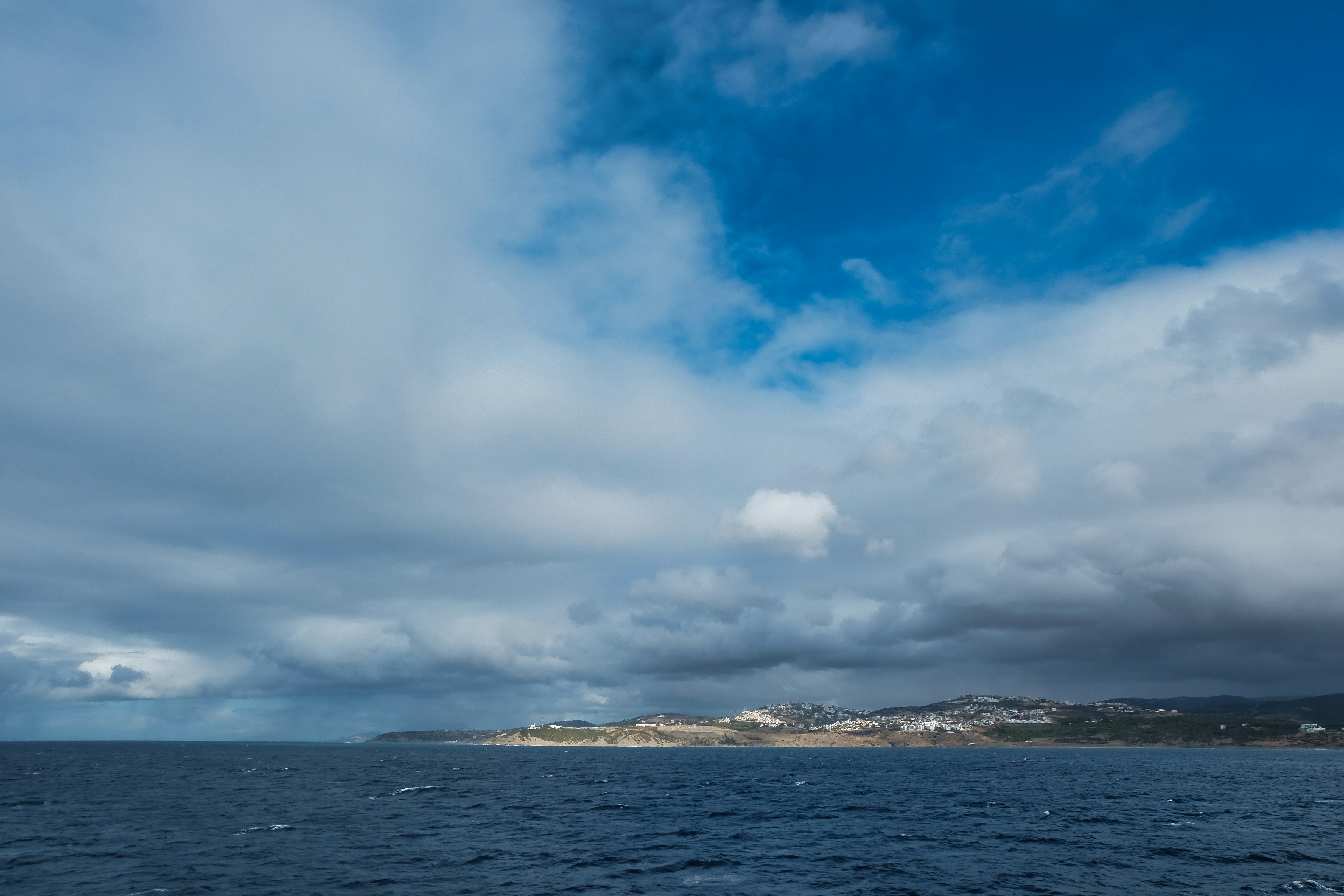 Distant coastal town under a dramatic cloudy sky.