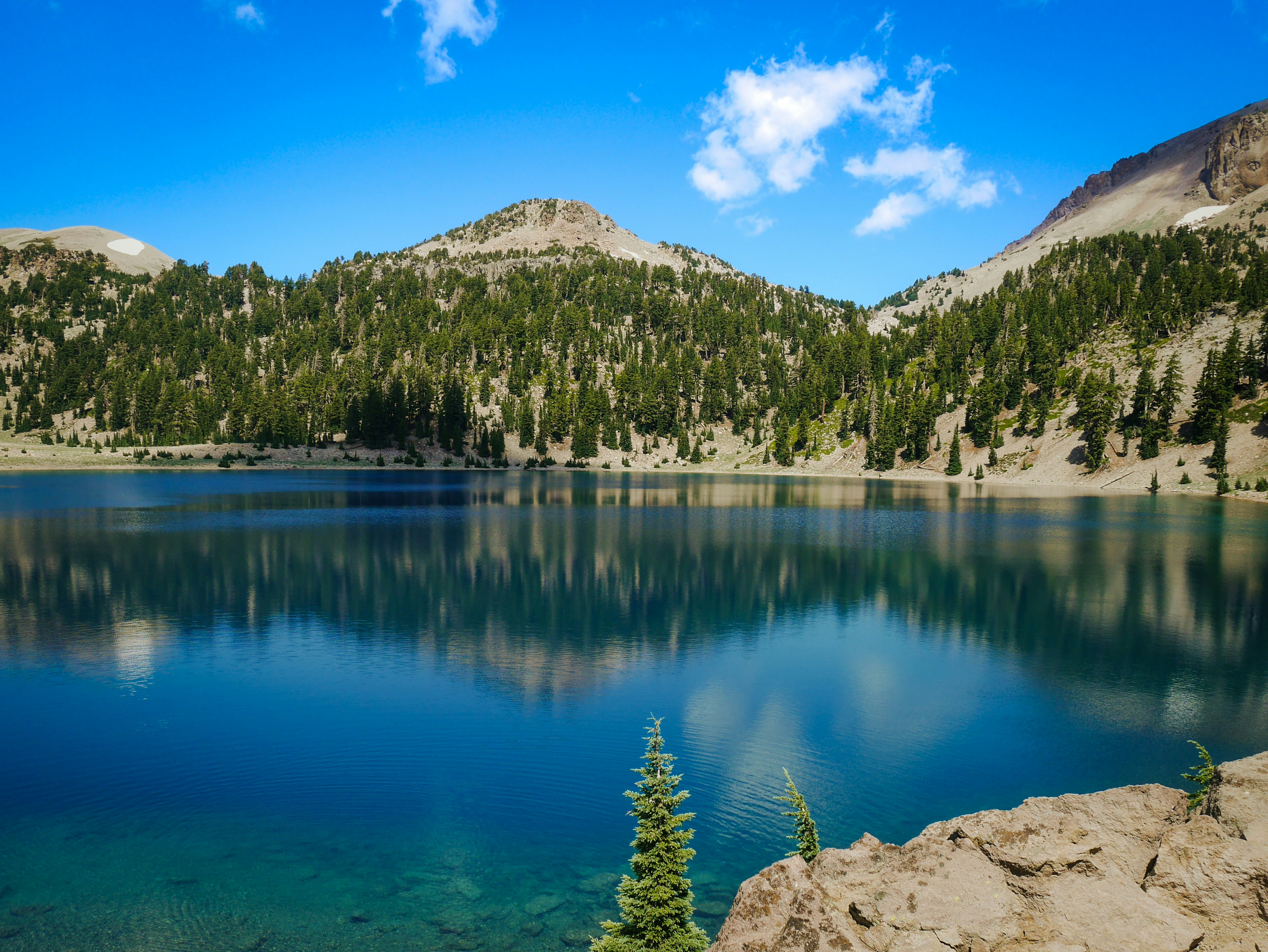 Tranquil mountain lake reflecting vibrant blue skies and lush greenery. The serene landscape invites contemplation and connection with nature.