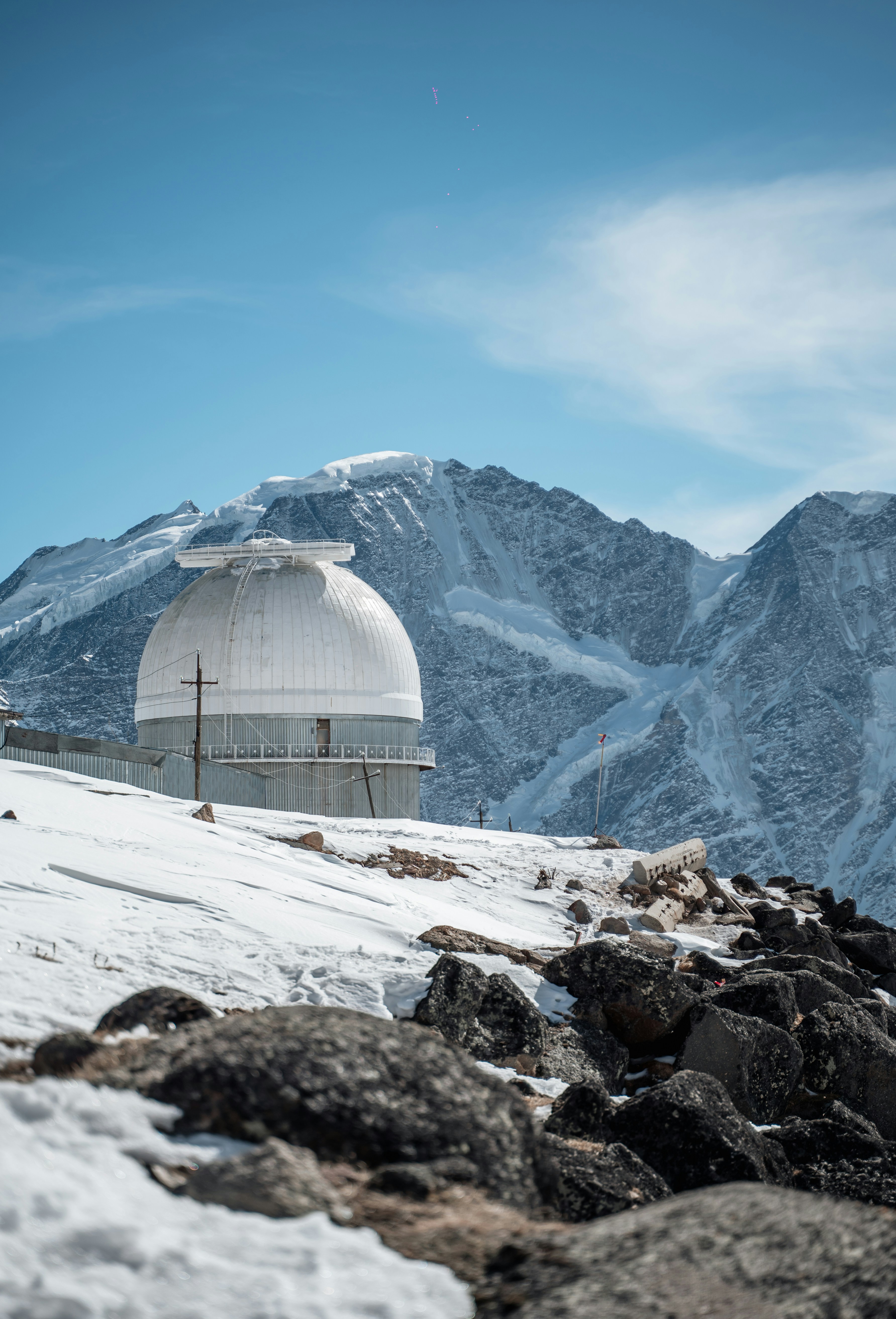 Observatory dome on snowy mountain under clear blue sky