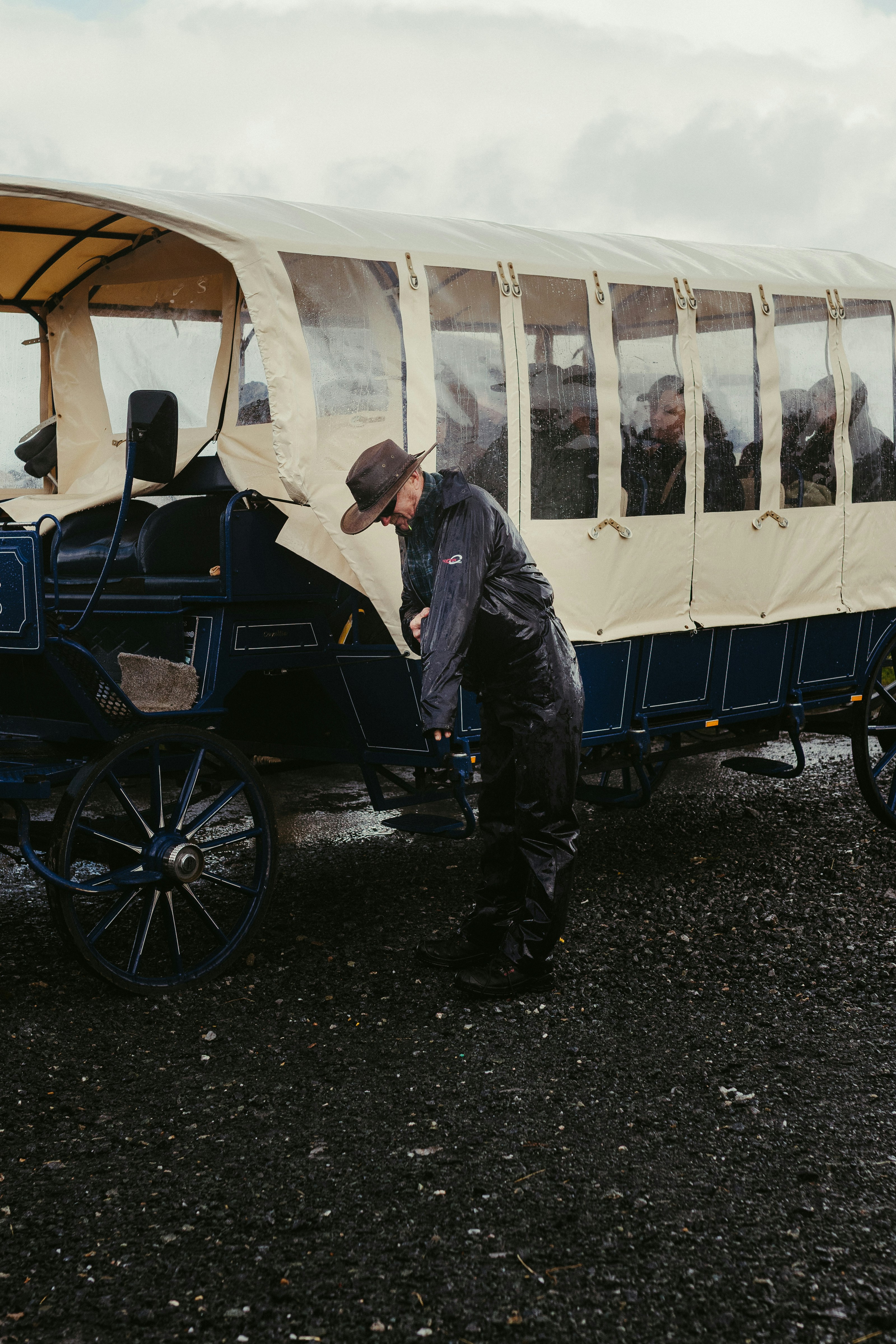 Man in hat tending to horse-drawn carriage with passengers