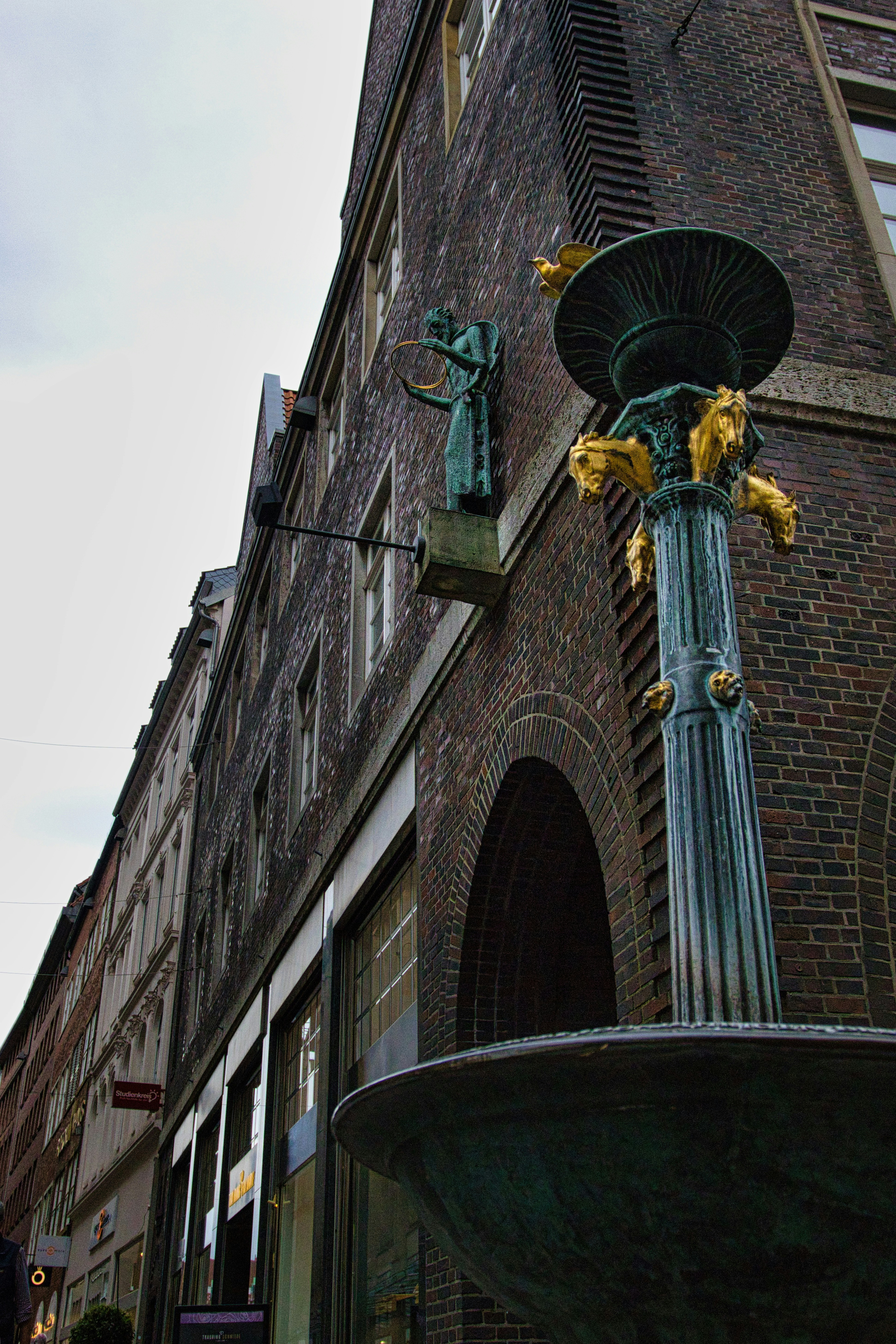 Ornate fountain on a brick building corner.