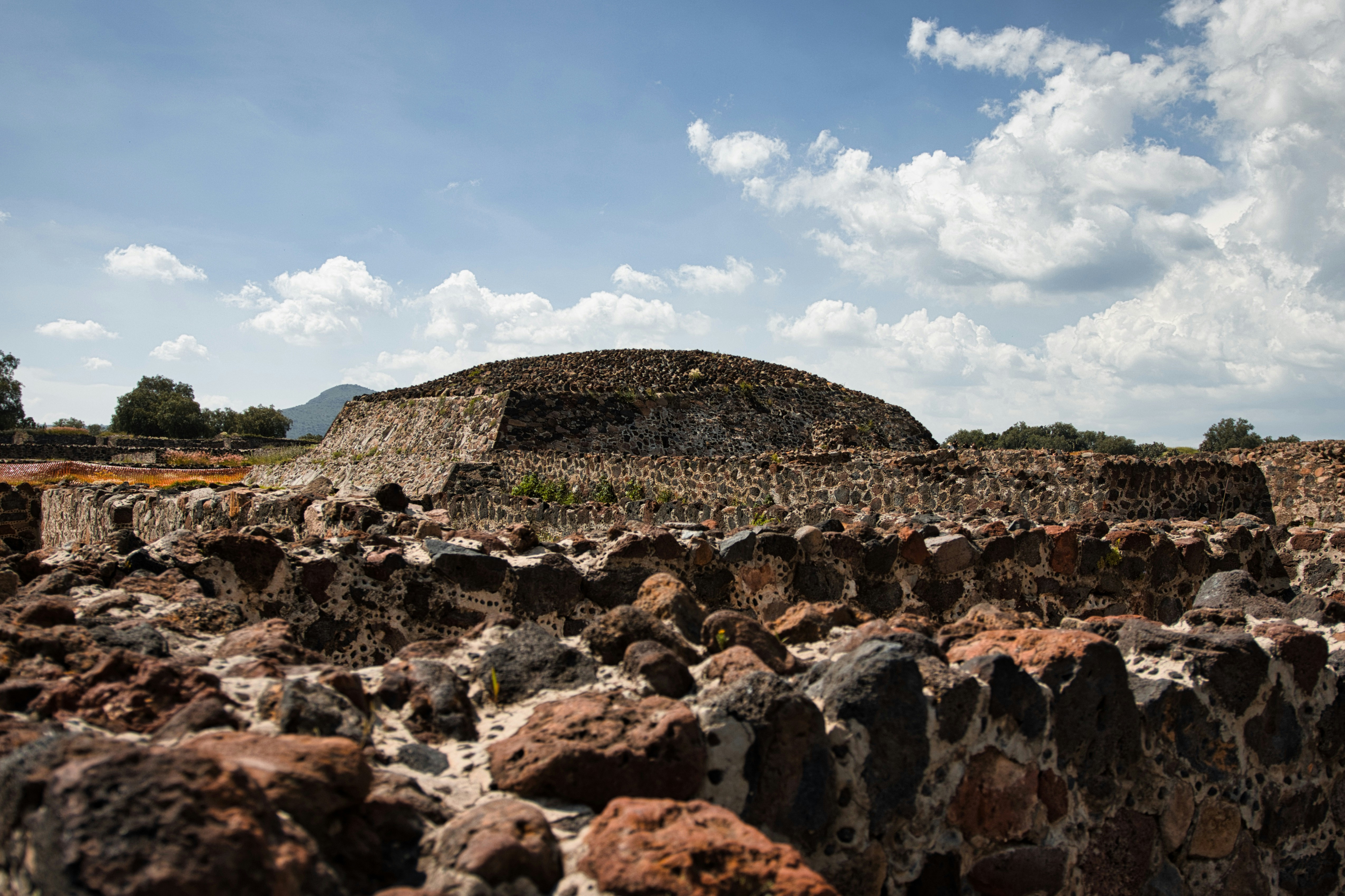 Ancient stone structures of Teotihuacan under a bright blue sky, showcasing the intricate texture of volcanic rock and remnants of a once-thriving civilization.