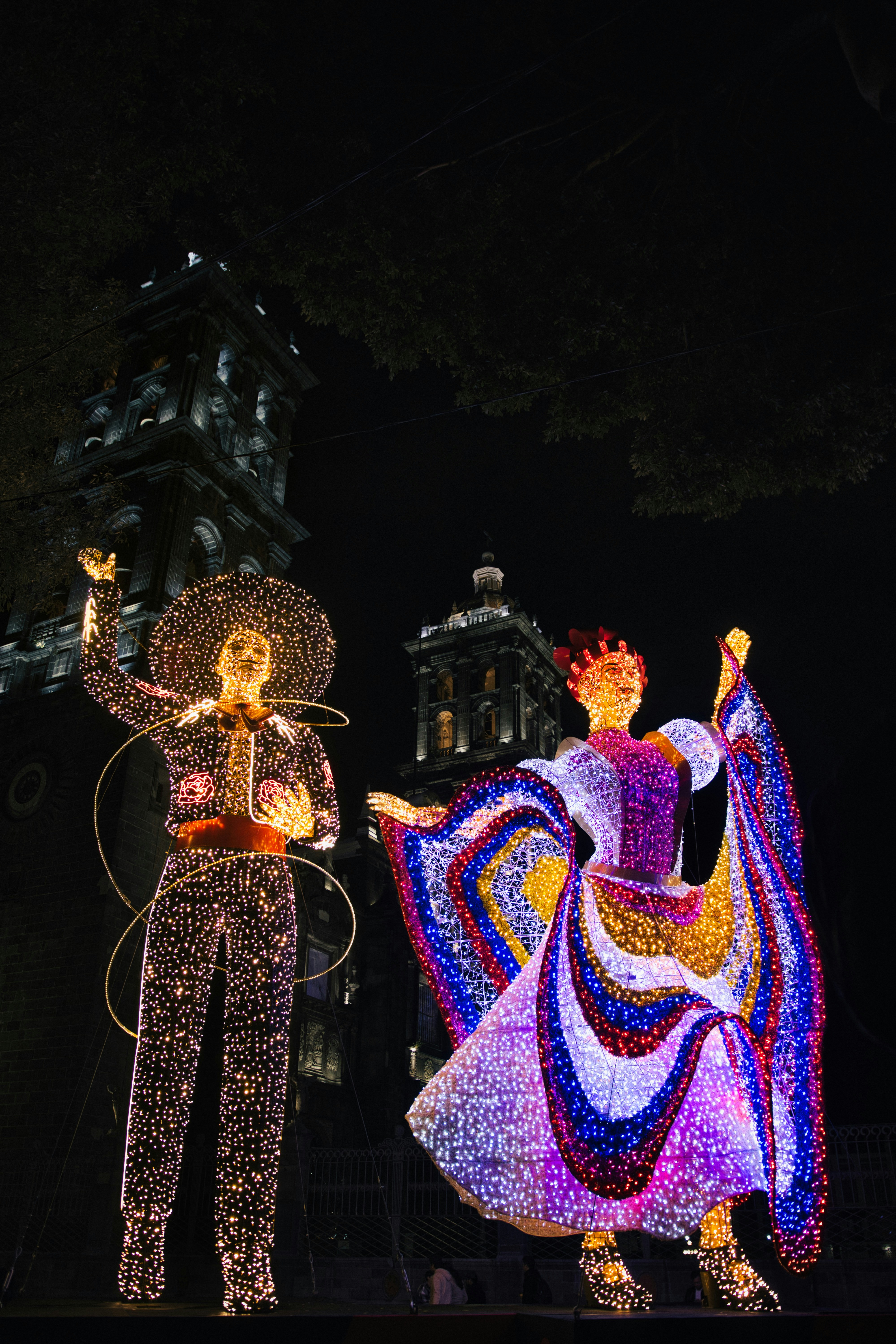 Illuminated figures of a mariachi and dancer at night