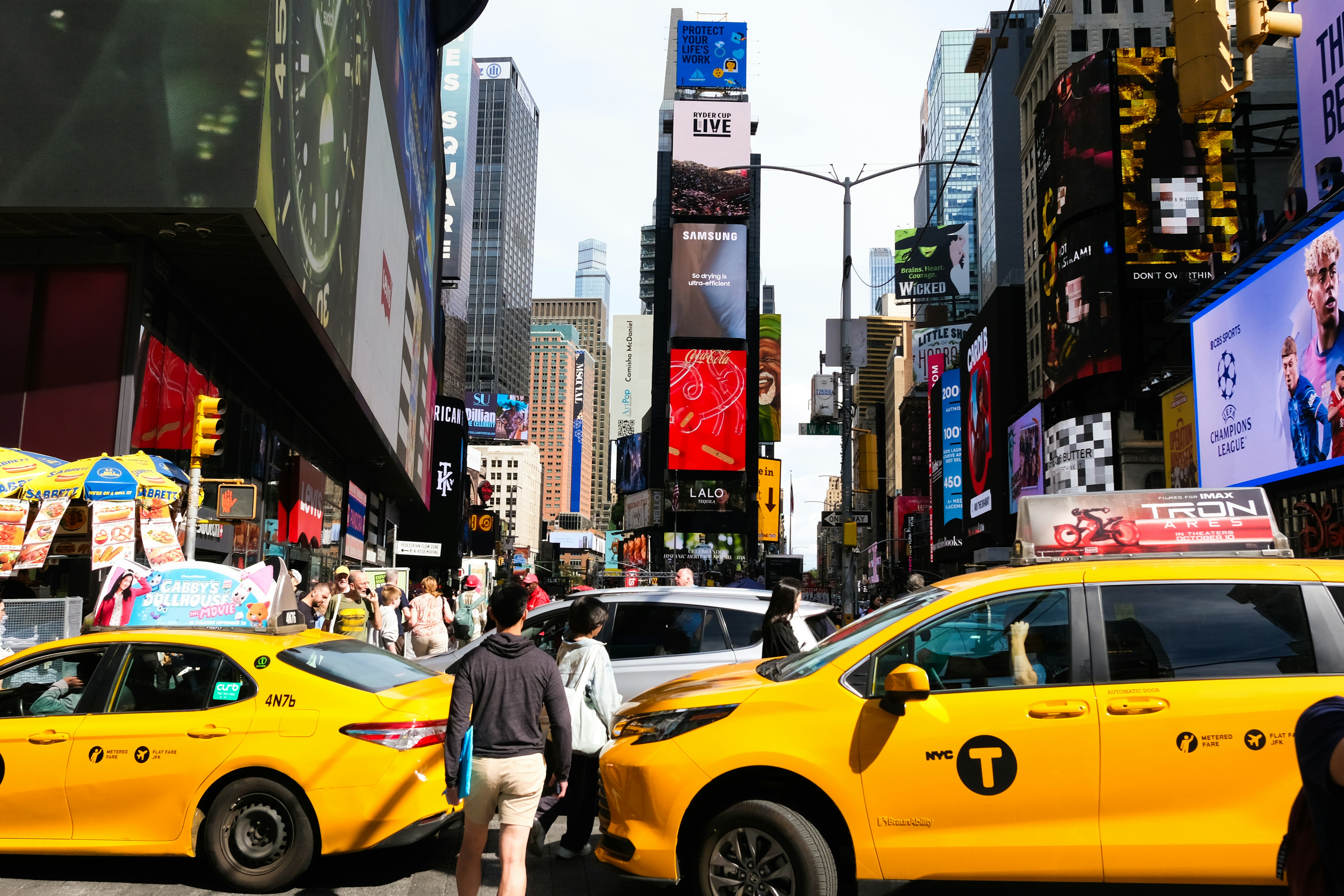 Vibrant scene of Times Square bustling with yellow taxis and pedestrians amidst bright advertisements and skyscrapers. The heart of New York City comes alive.