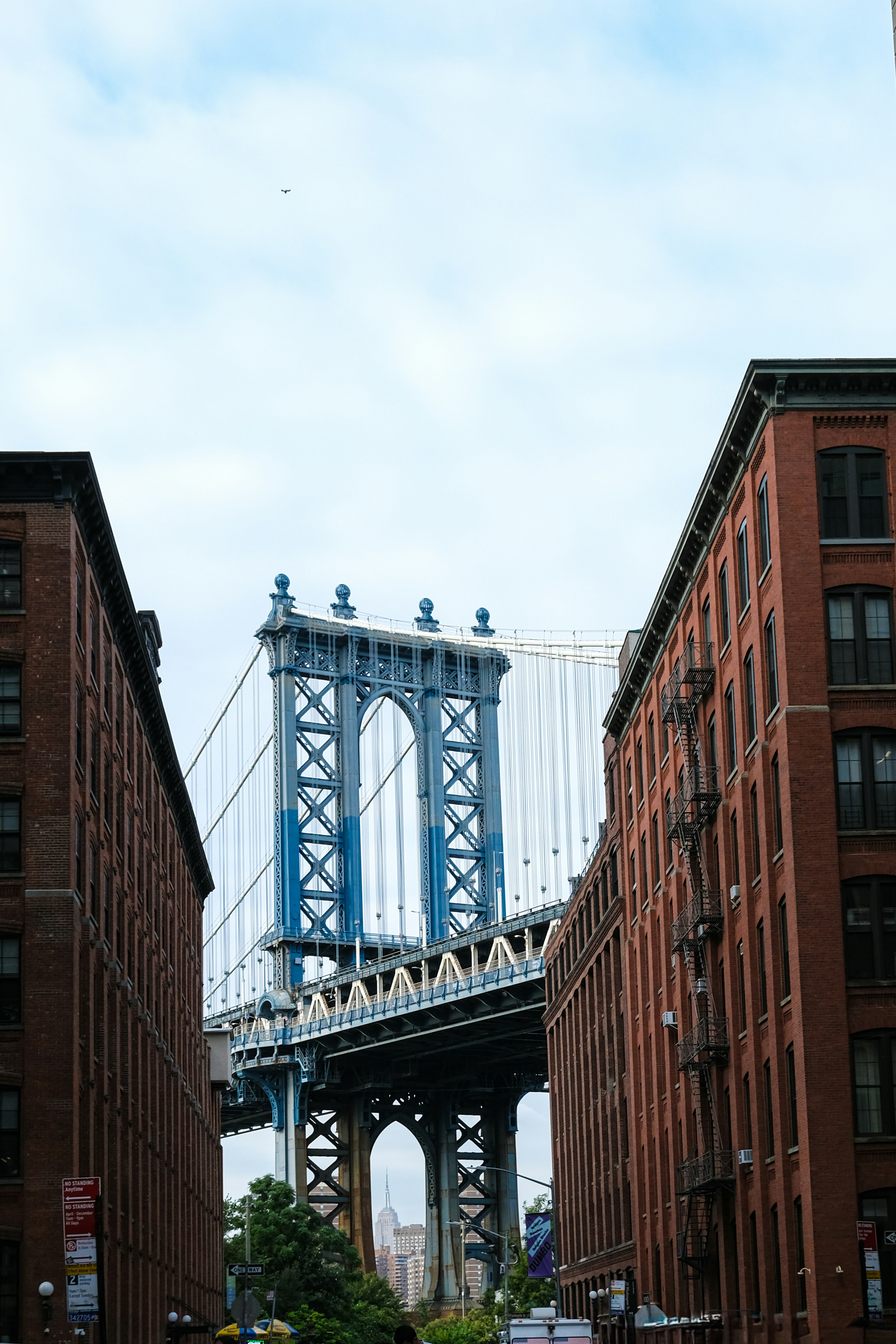 Manhattan bridge viewed between brick buildings