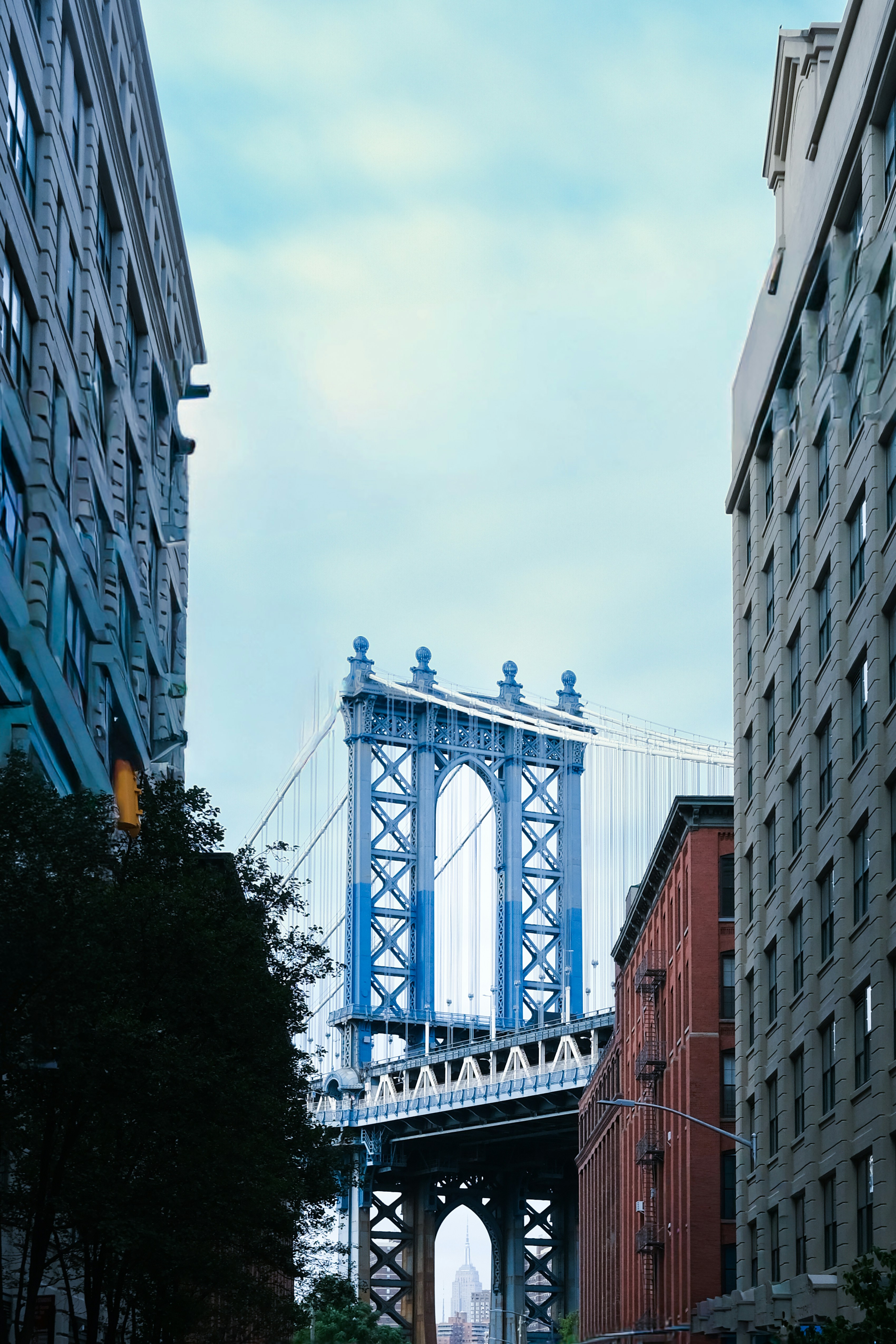 Manhattan Bridge framed by urban architecture, showcasing a blend of city life and engineering marvels.