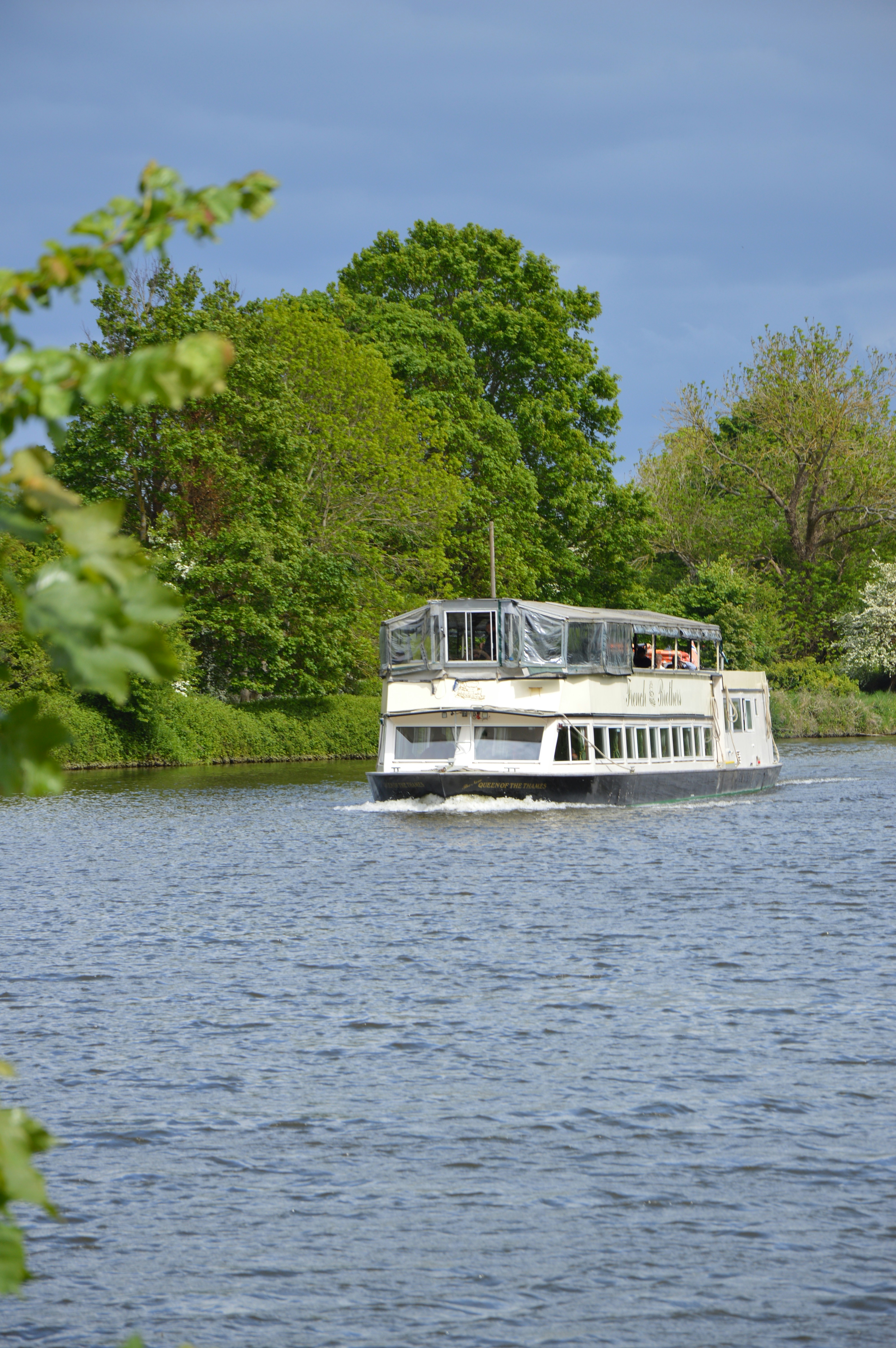 A white passenger boat travels on a wide river.