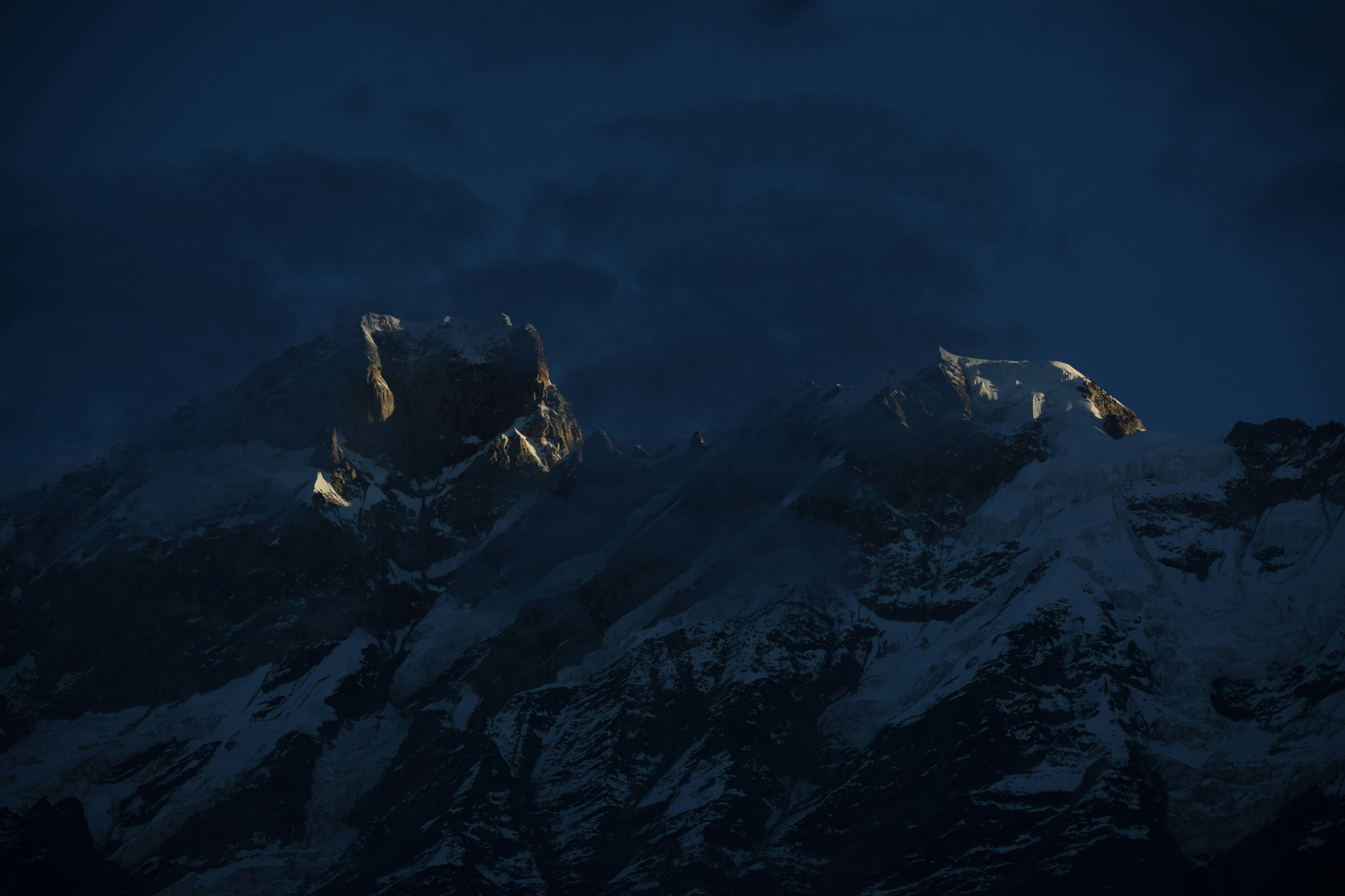 Snow-capped mountains illuminated by moonlight at night