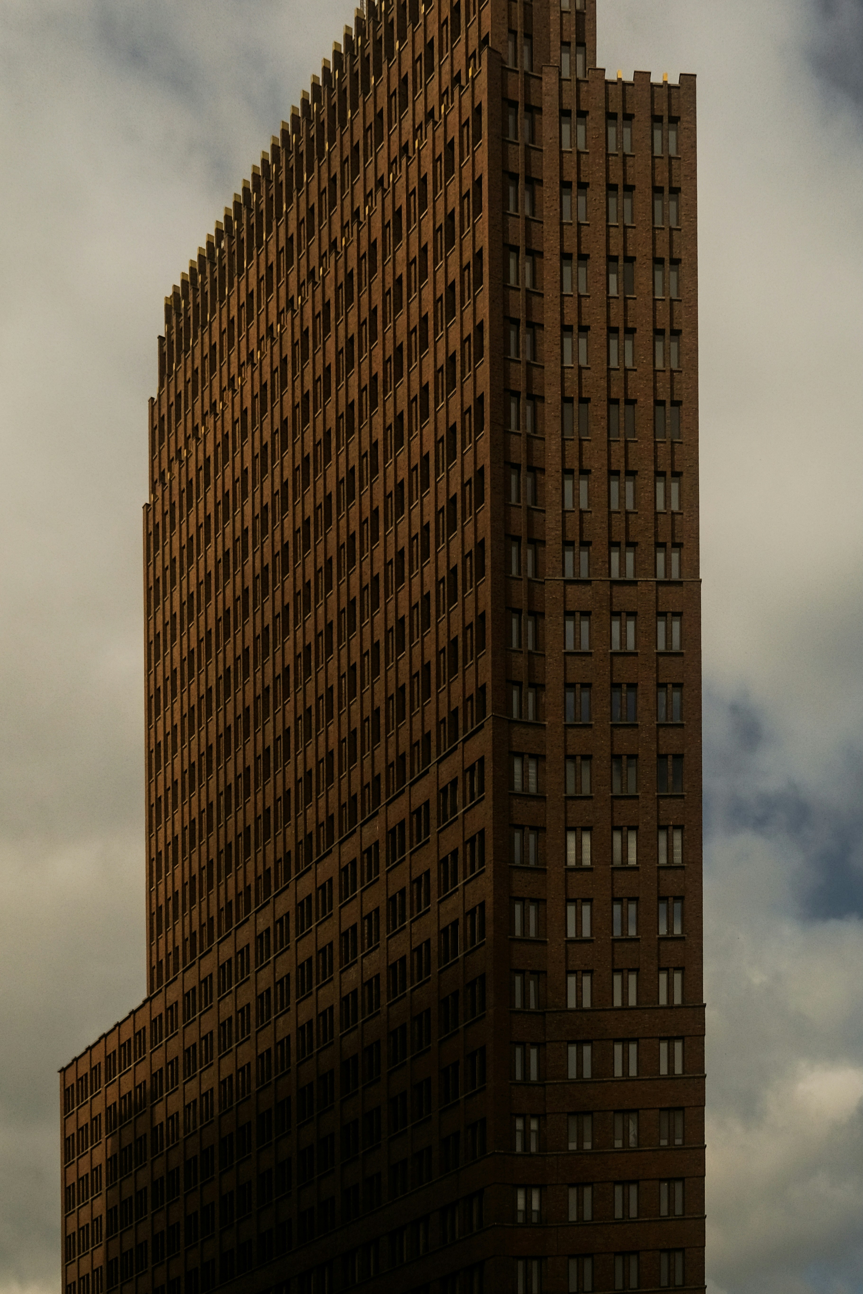 Tall brown skyscraper against a cloudy sky