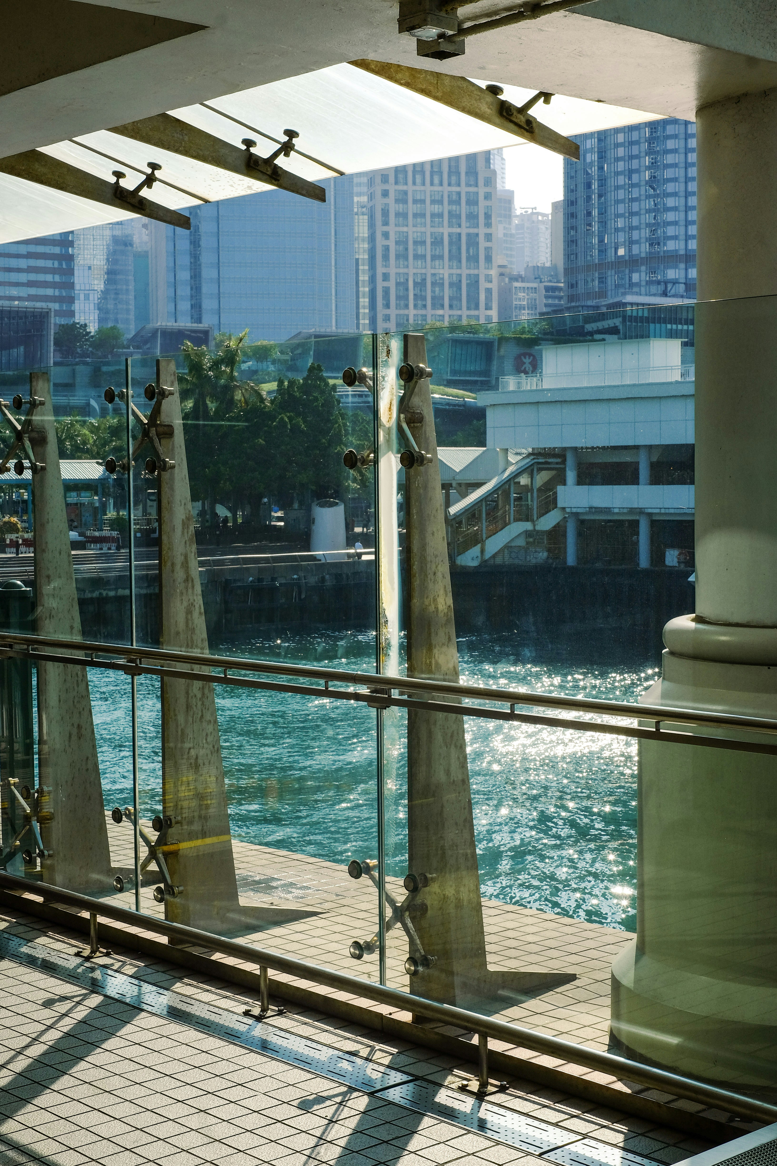 Columns, Glass, and Water: A Sunlit City Walkway Framing the Skyline