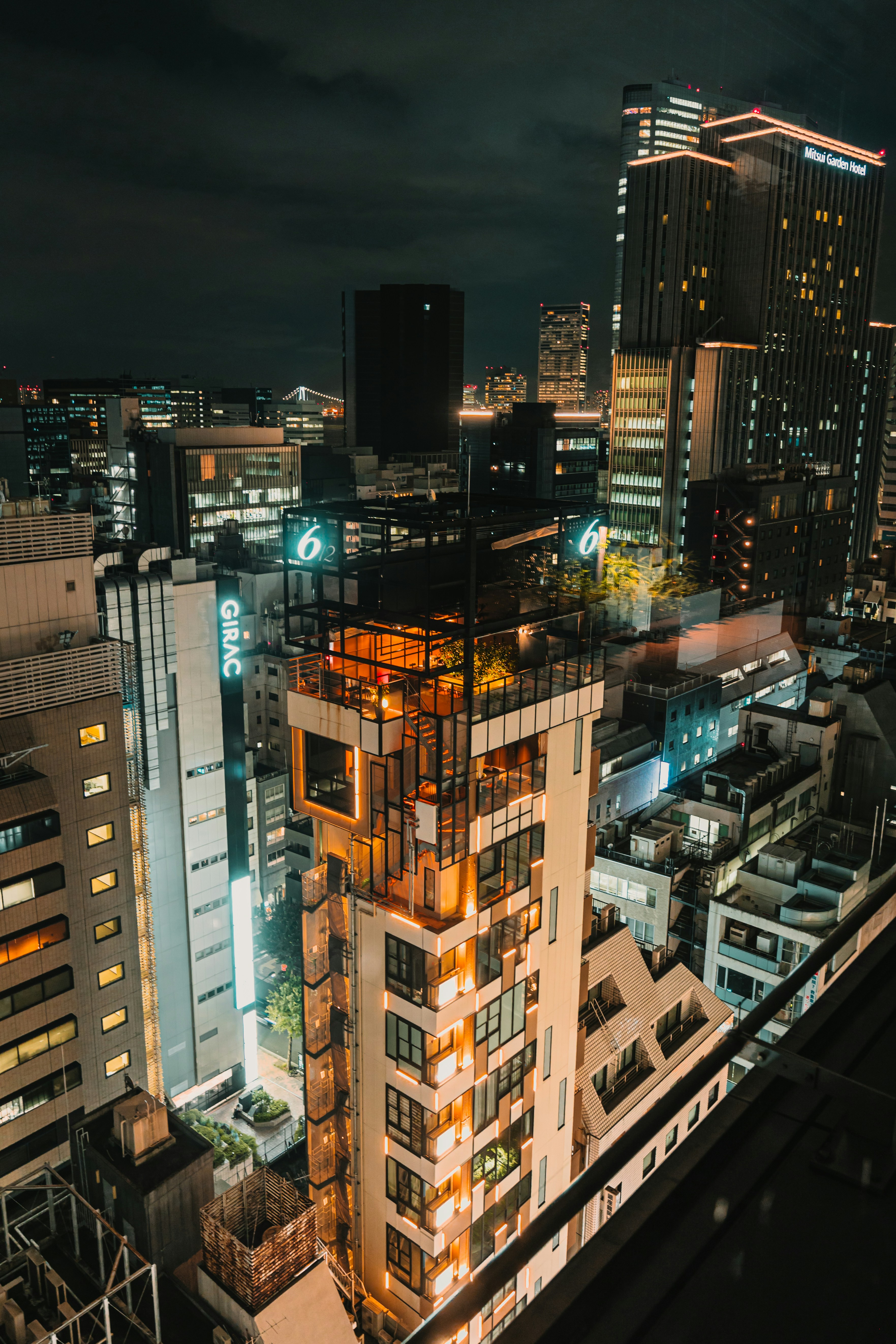 Illuminated city buildings at night with glowing windows.