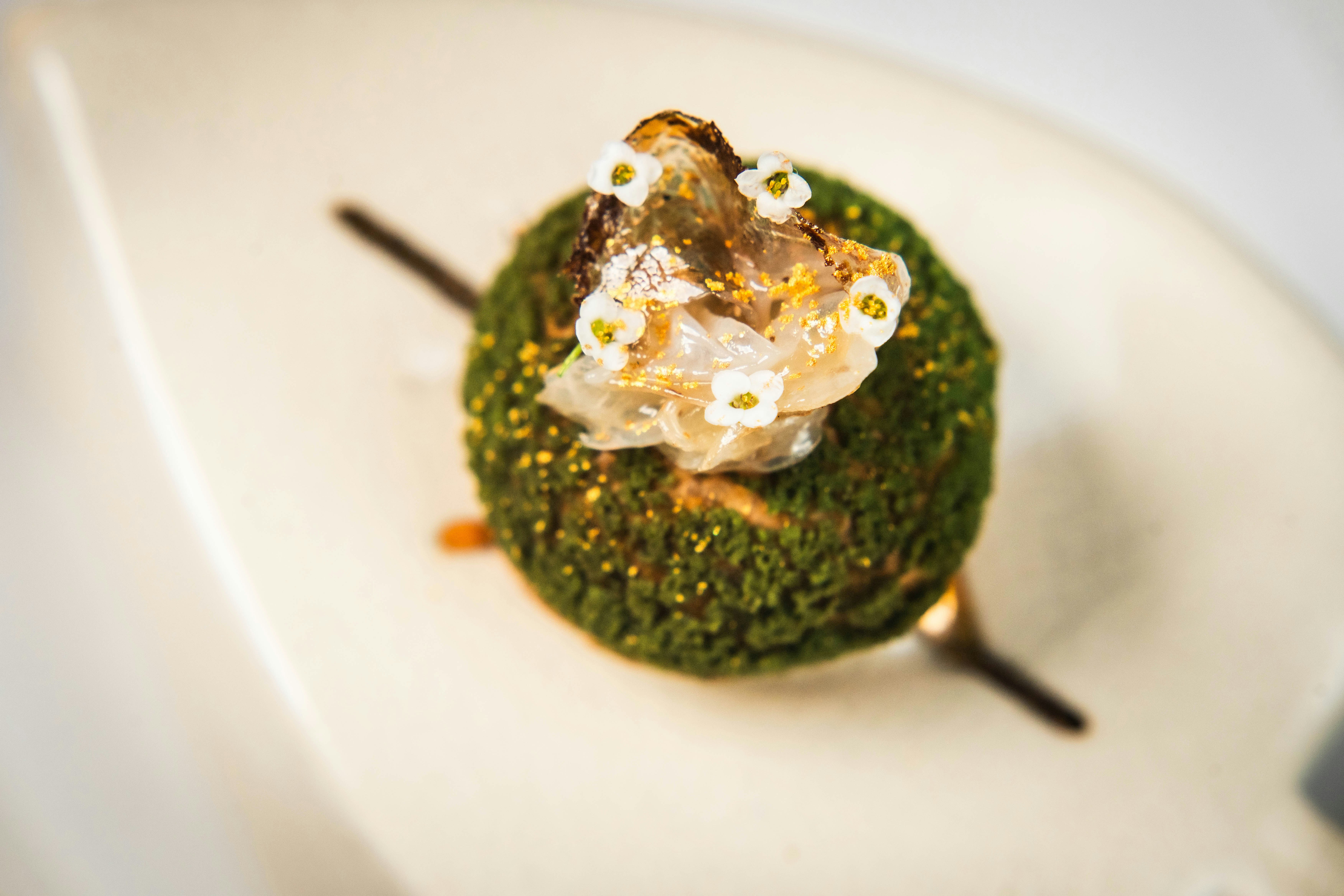 Gourmet green dessert with white flowers and gold sprinkles
