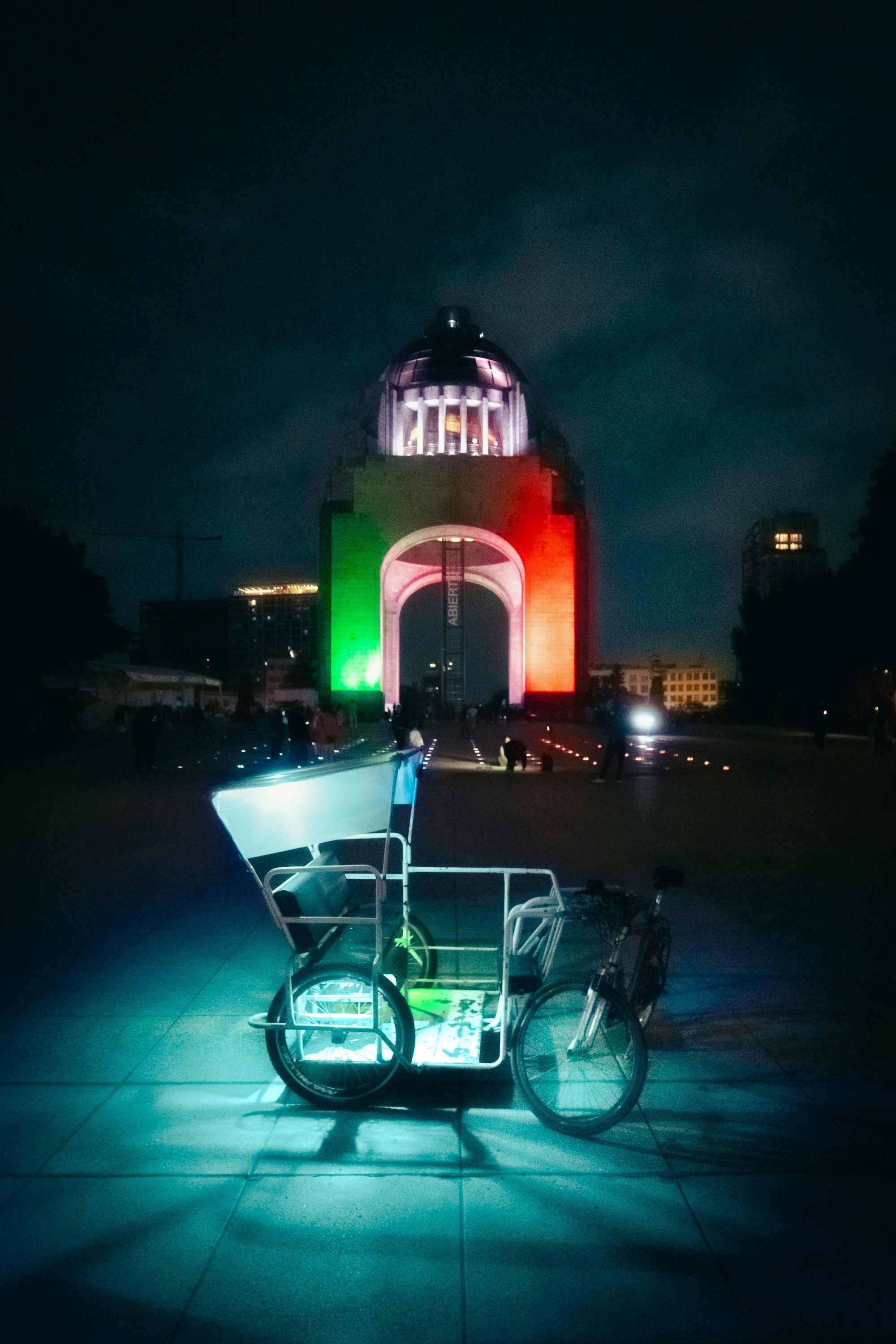 Rickshaw illuminated at night with monument in background