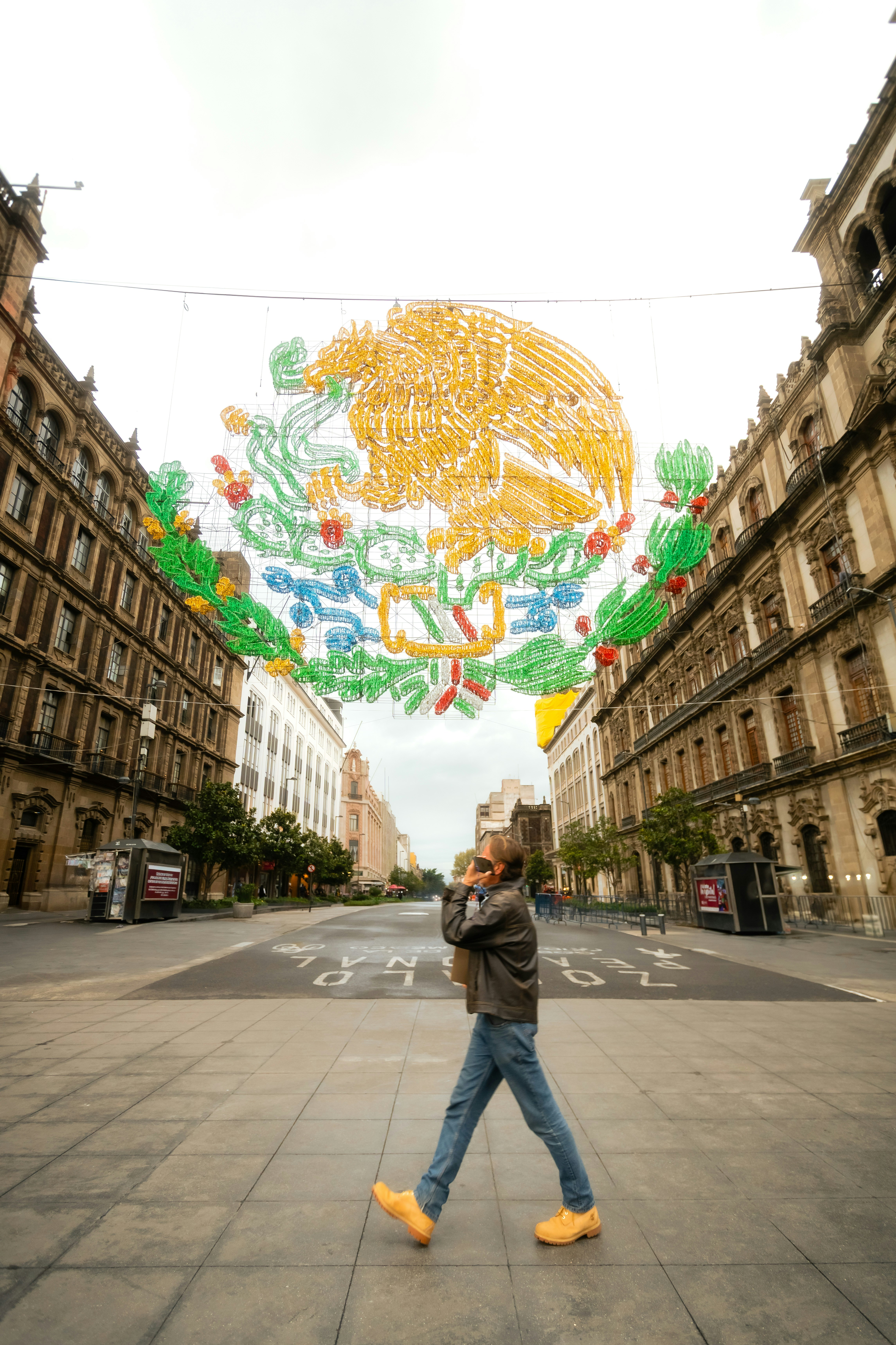 Person walks down street with mexican flag decoration.