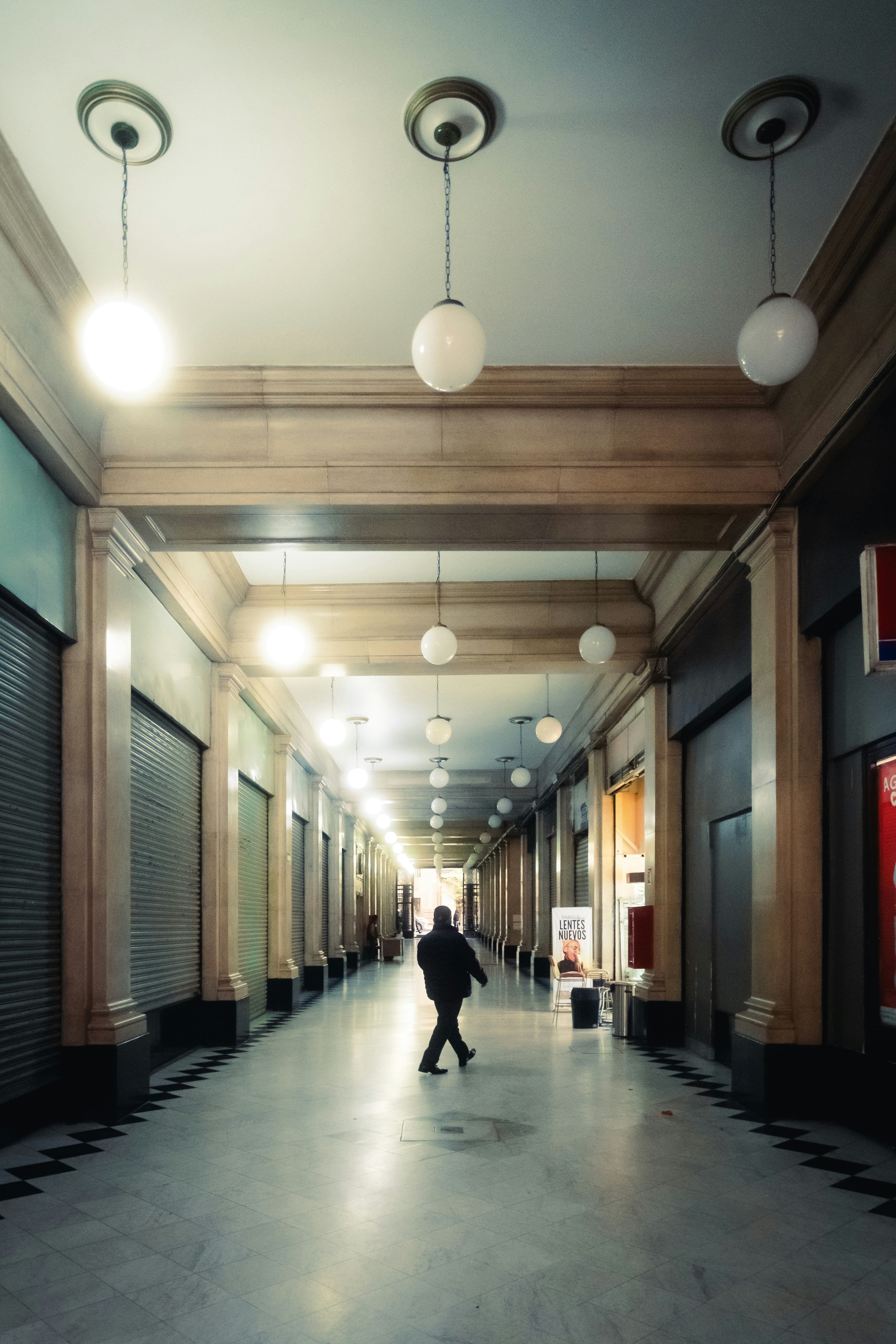 Person walking down a long, lit arcade hallway.