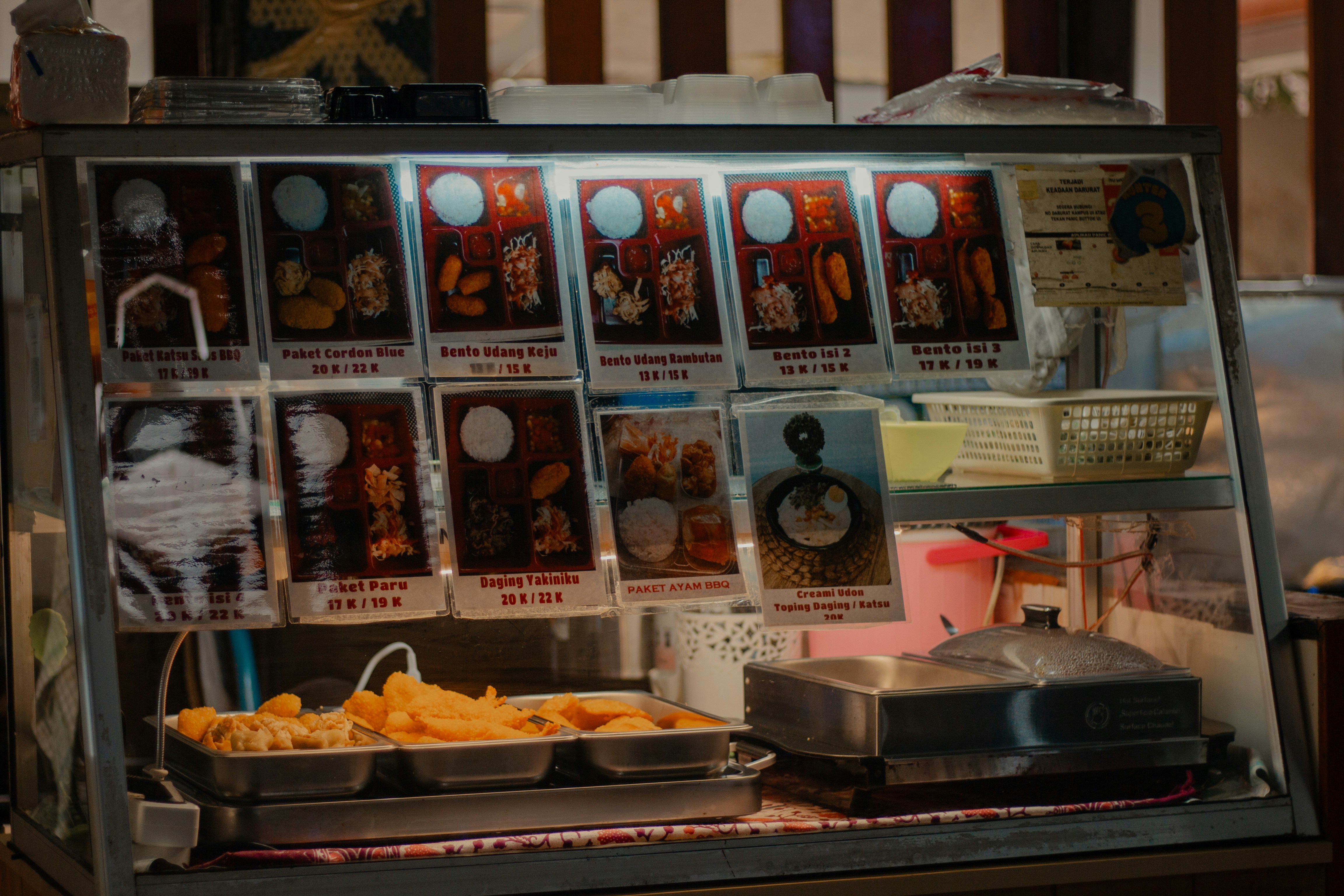 Food stall in Universitas Indonesia | Food display case with fried snacks and menus